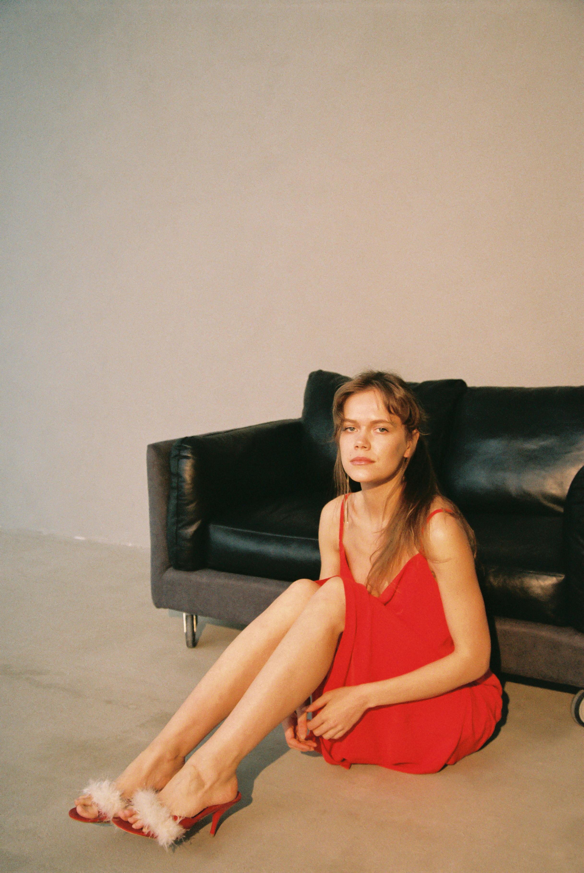 Woman Sitting on the Floor Leaning Against a Couch · Free Stock Photo