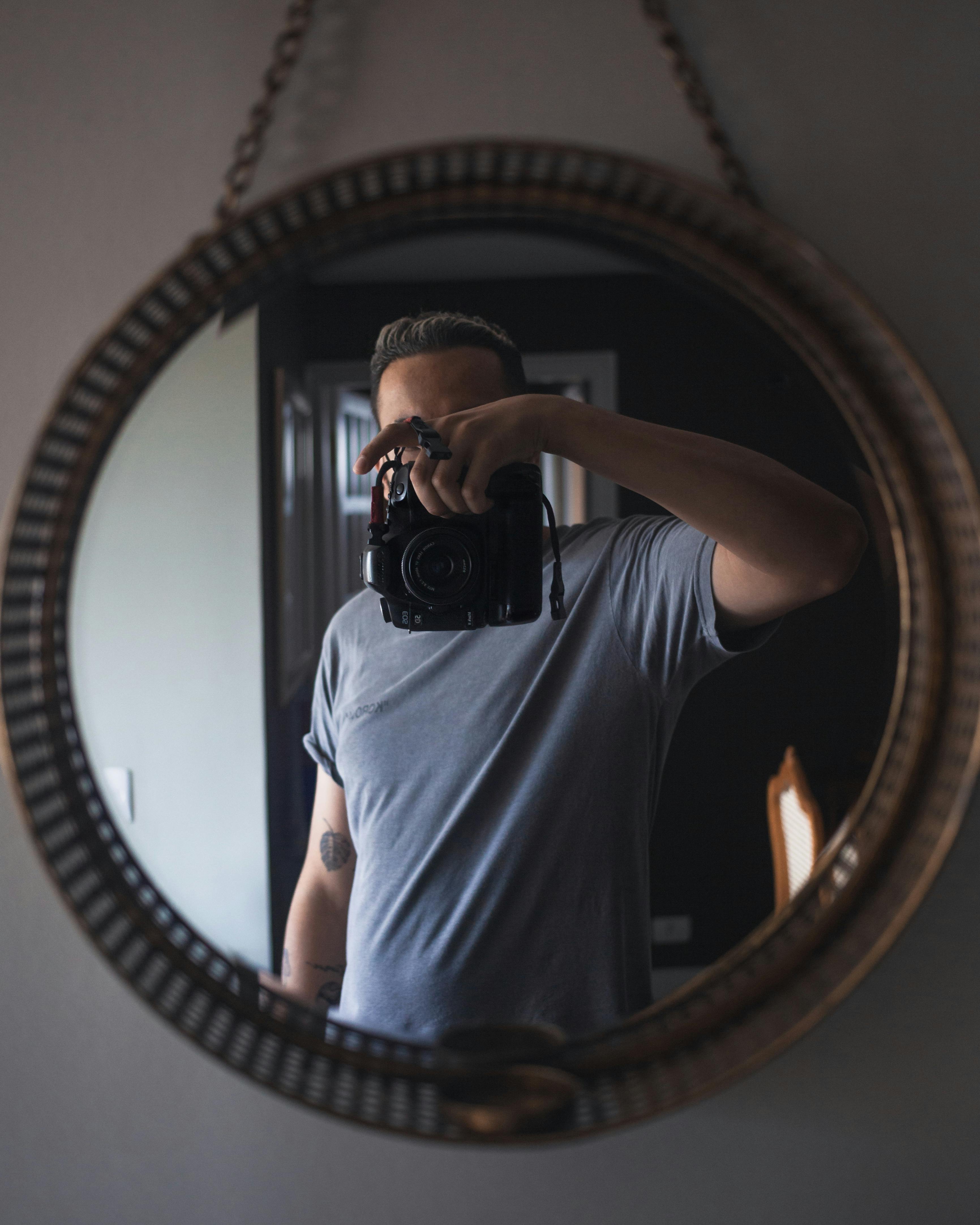 Person Reflect on Round Brown Wooden-framed Mirror · Free Stock Photo