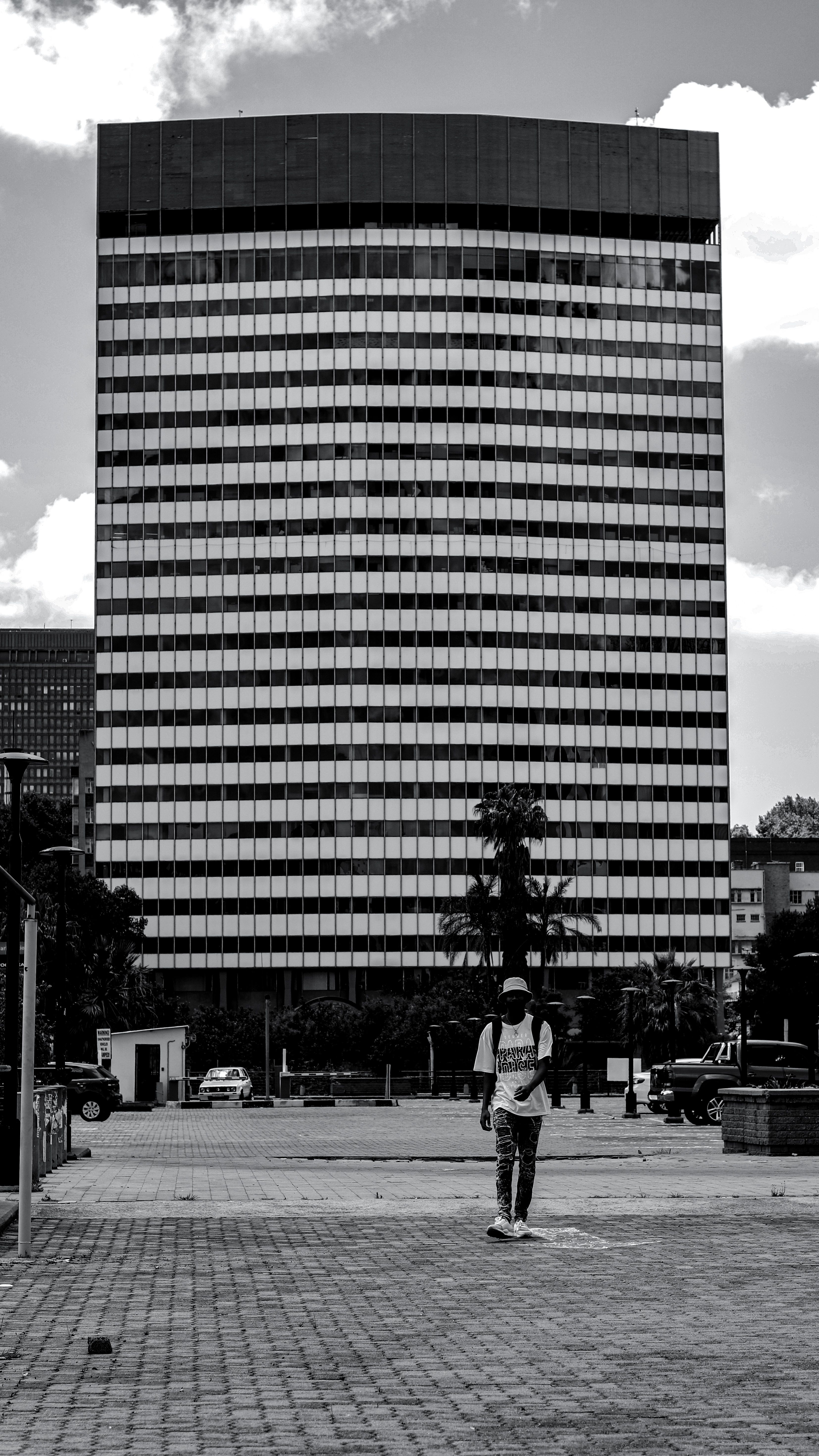 Grayscale Photo of a Person Walking on the Street near High Rise ...
