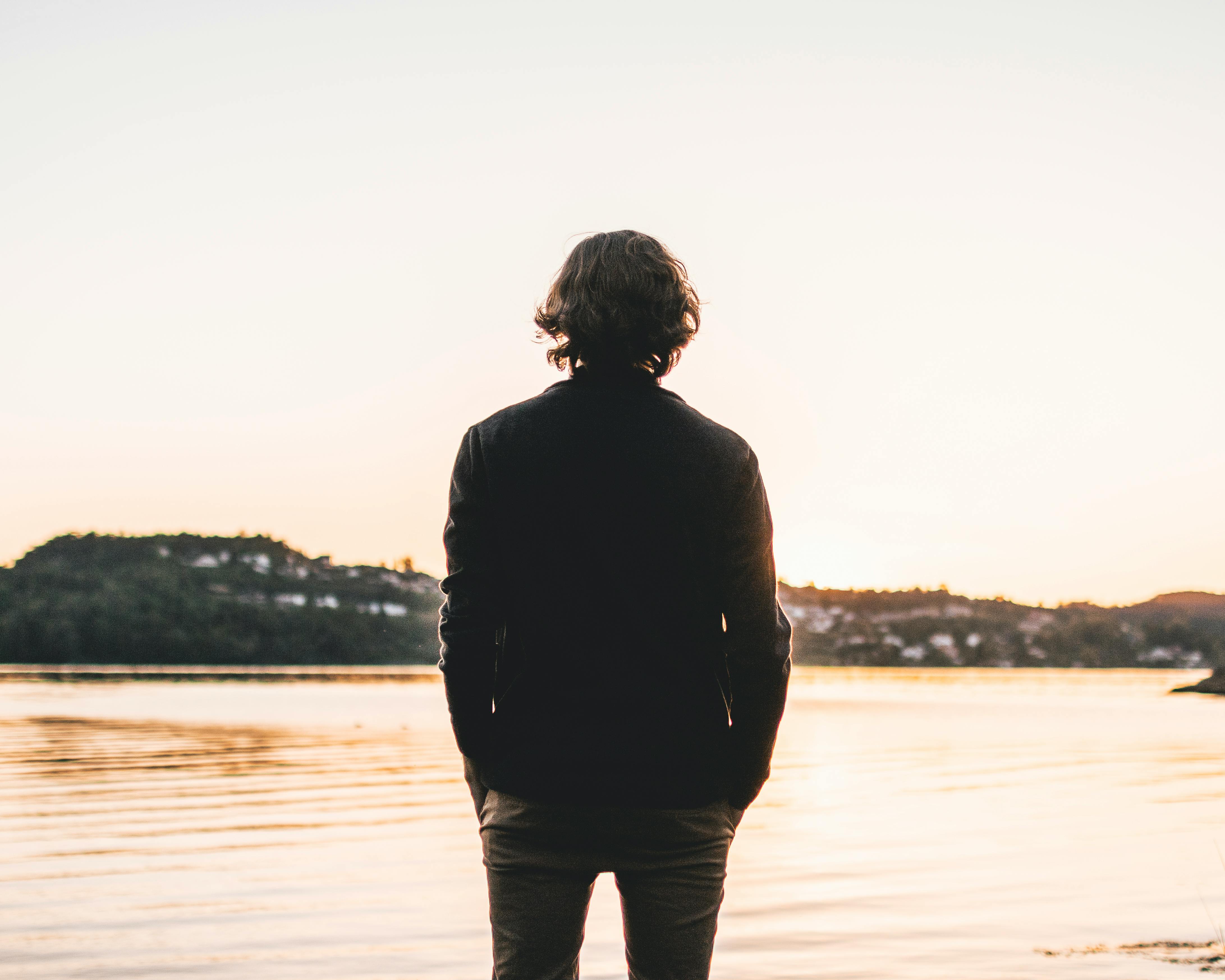 Man Standing Facing Body of Water · Free Stock Photo
