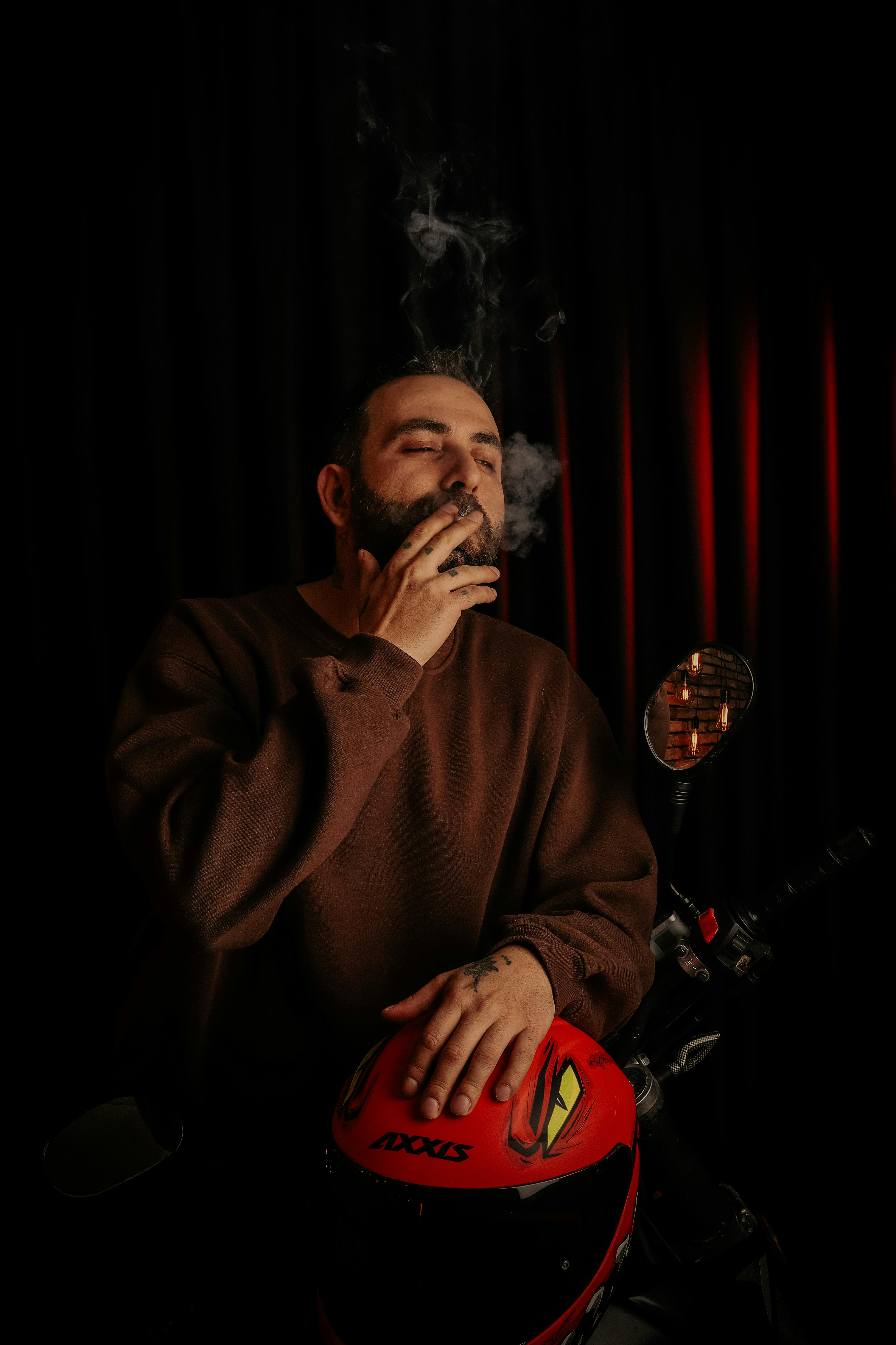 Close-Up Shot of a Man in Brown Long Sleeve Smoking while Holding a ...