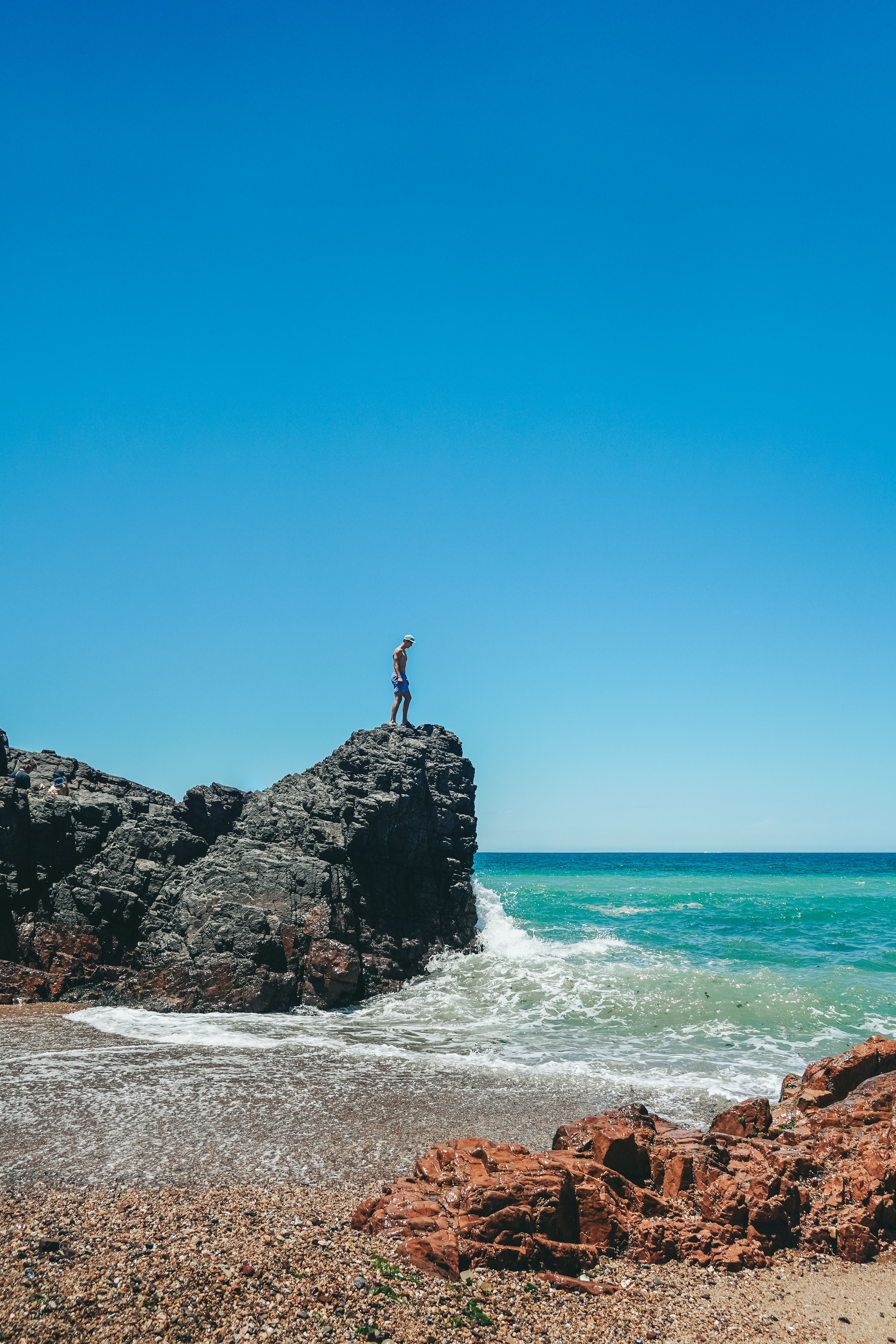 Person Standing on a Rock Formation Beside the Sea · Free Stock Photo