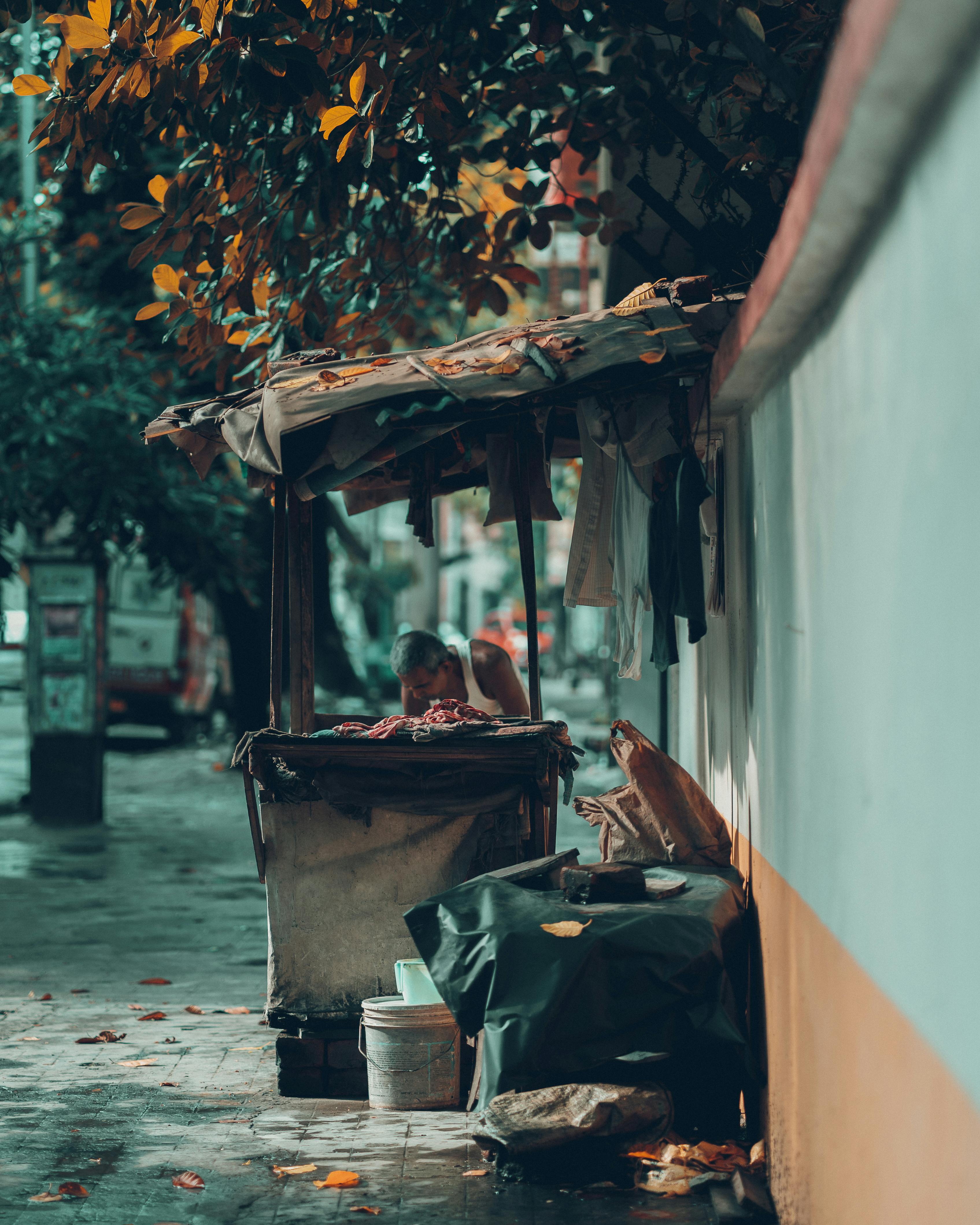 Man Stooping Down by a Vending Stall on a Street · Free Stock Photo