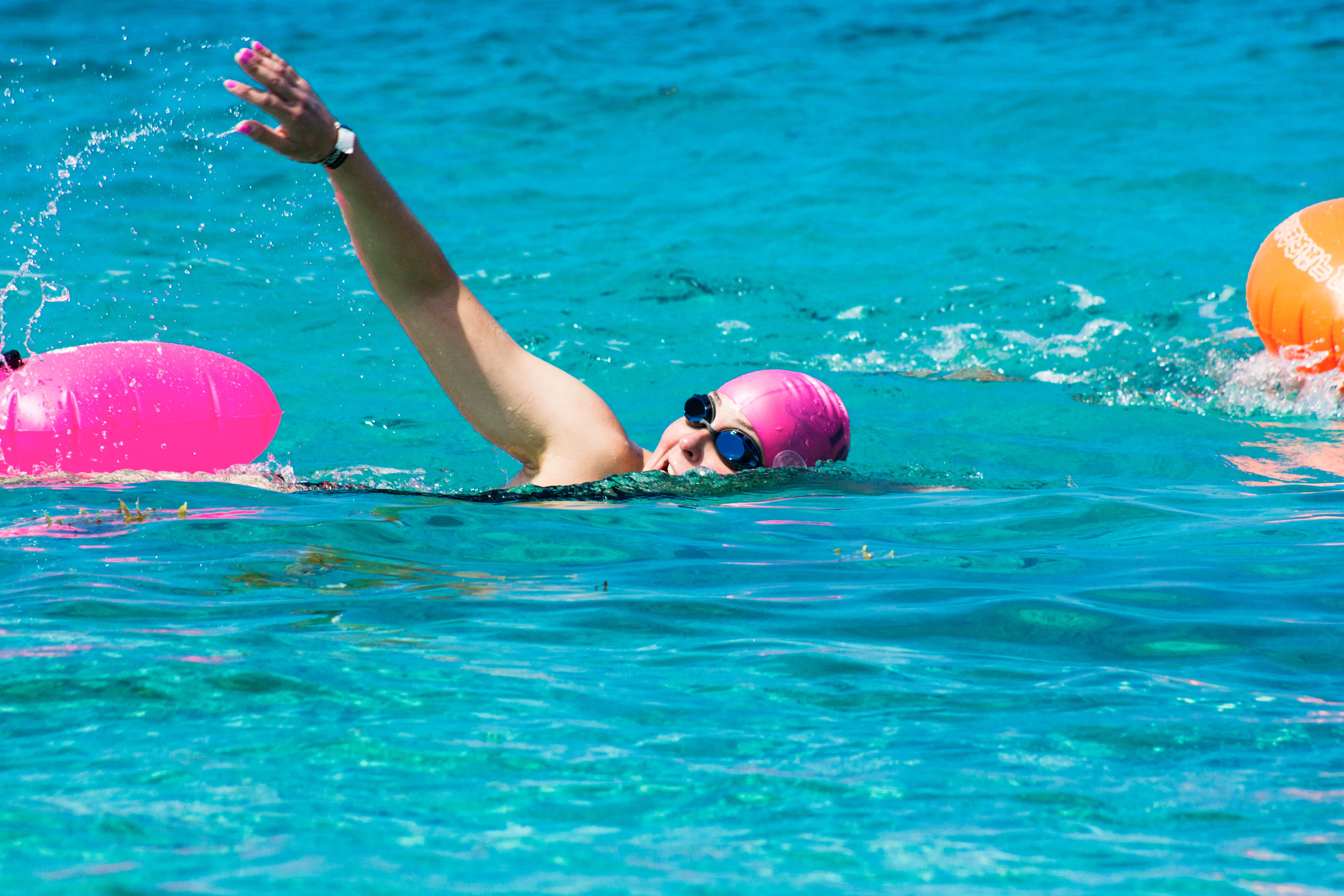 A Woman Wearing Goggles and Swimming Cap While Swimming in a Pool ...