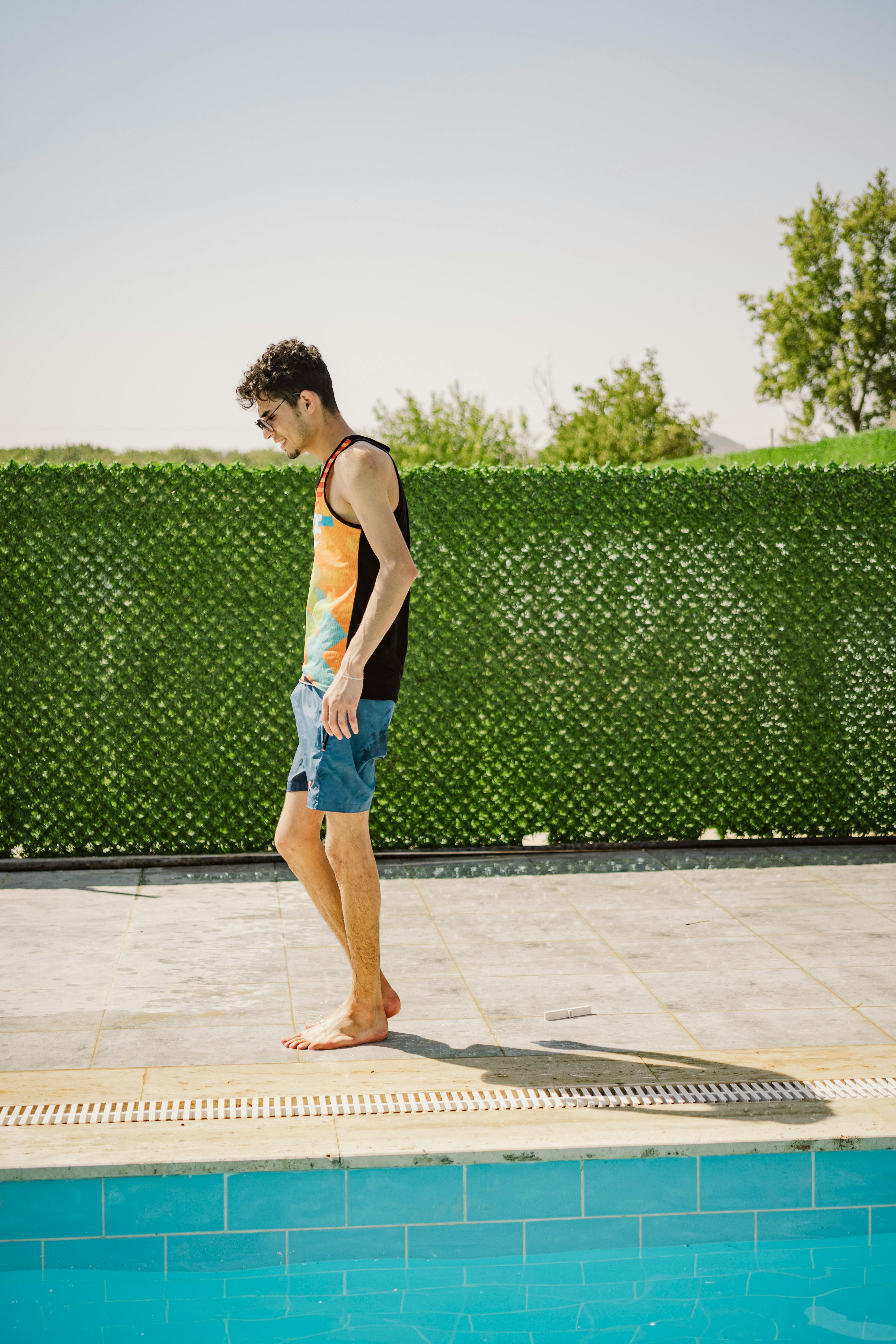 A Side View of a Man Standing Near the Pool Side · Free Stock Photo