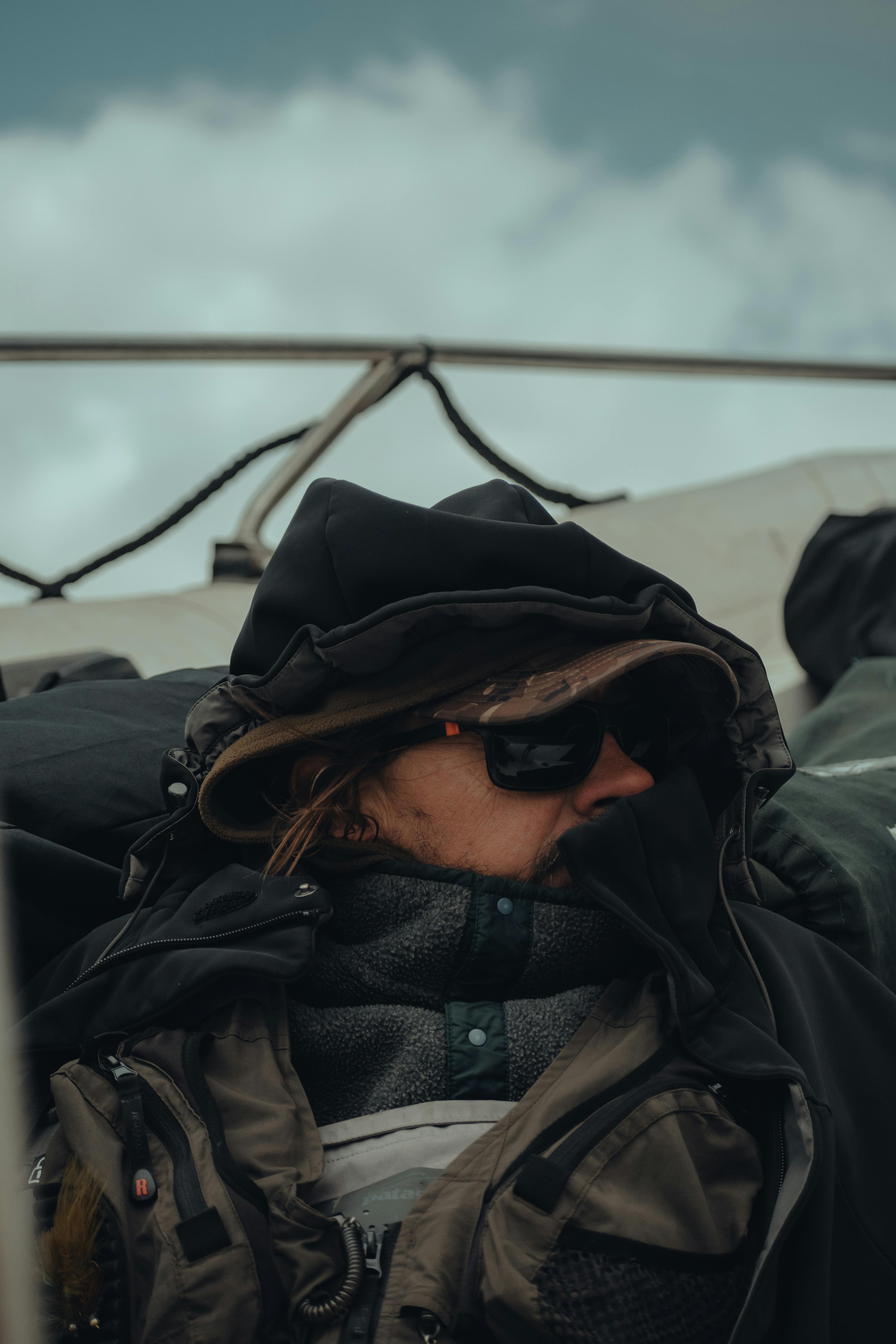 Man in Hooded Jacket Covering Face in Hand · Free Stock Photo