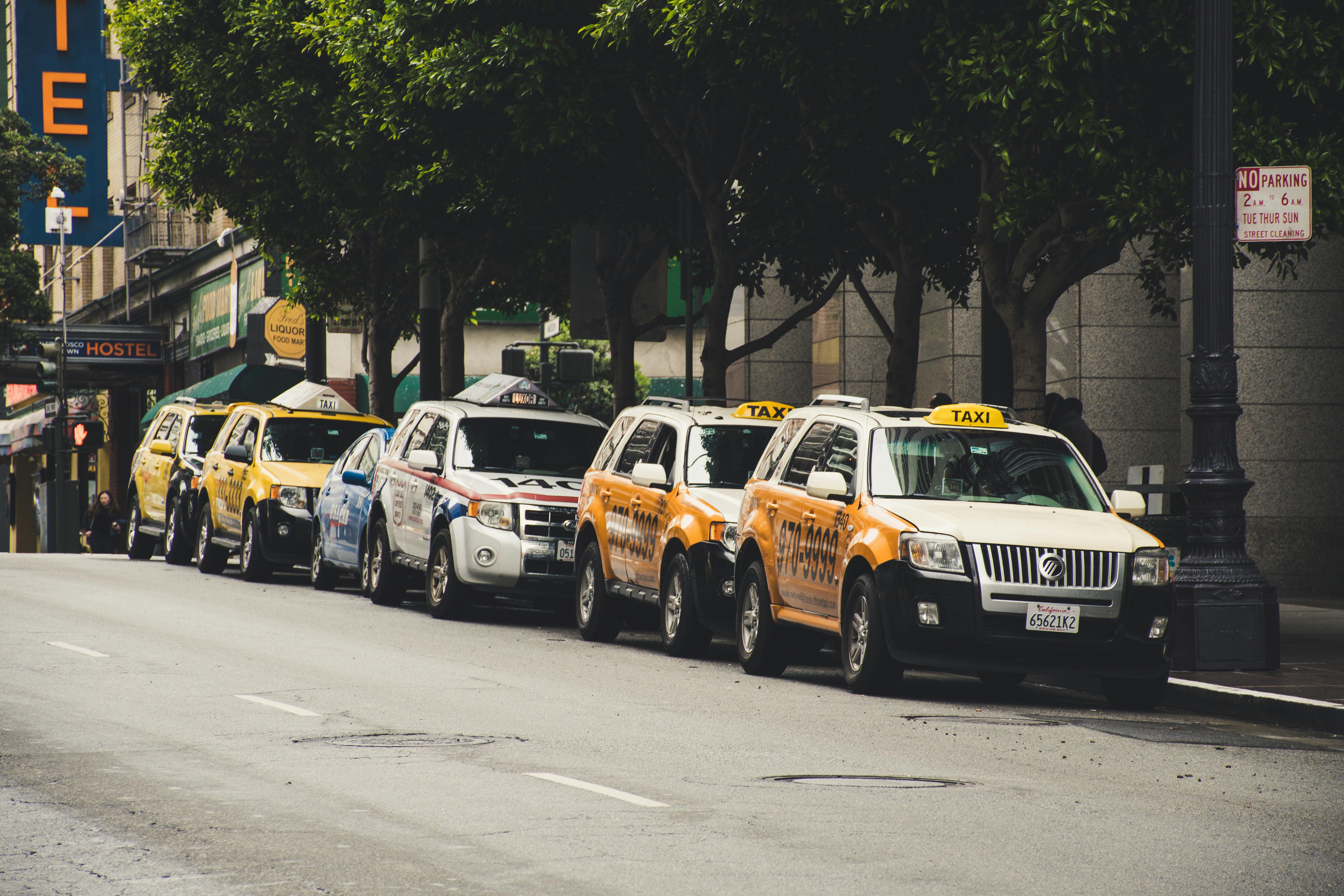 Yellow Taxi Vehicle Near Gray Concrete Building · Free Stock Photo