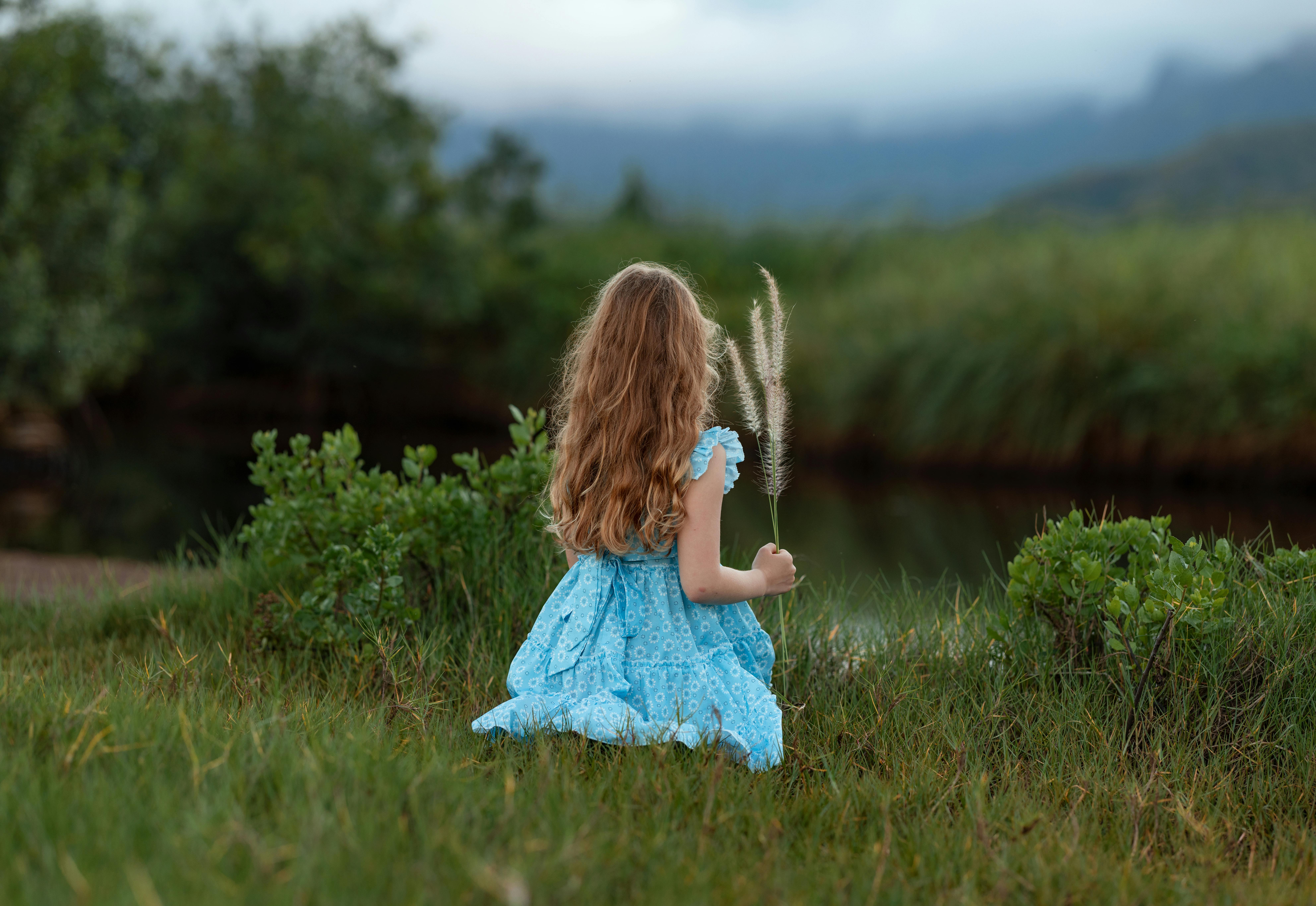 Girl Sitting on Grass Field Holding Pampas Grass · Free Stock Photo