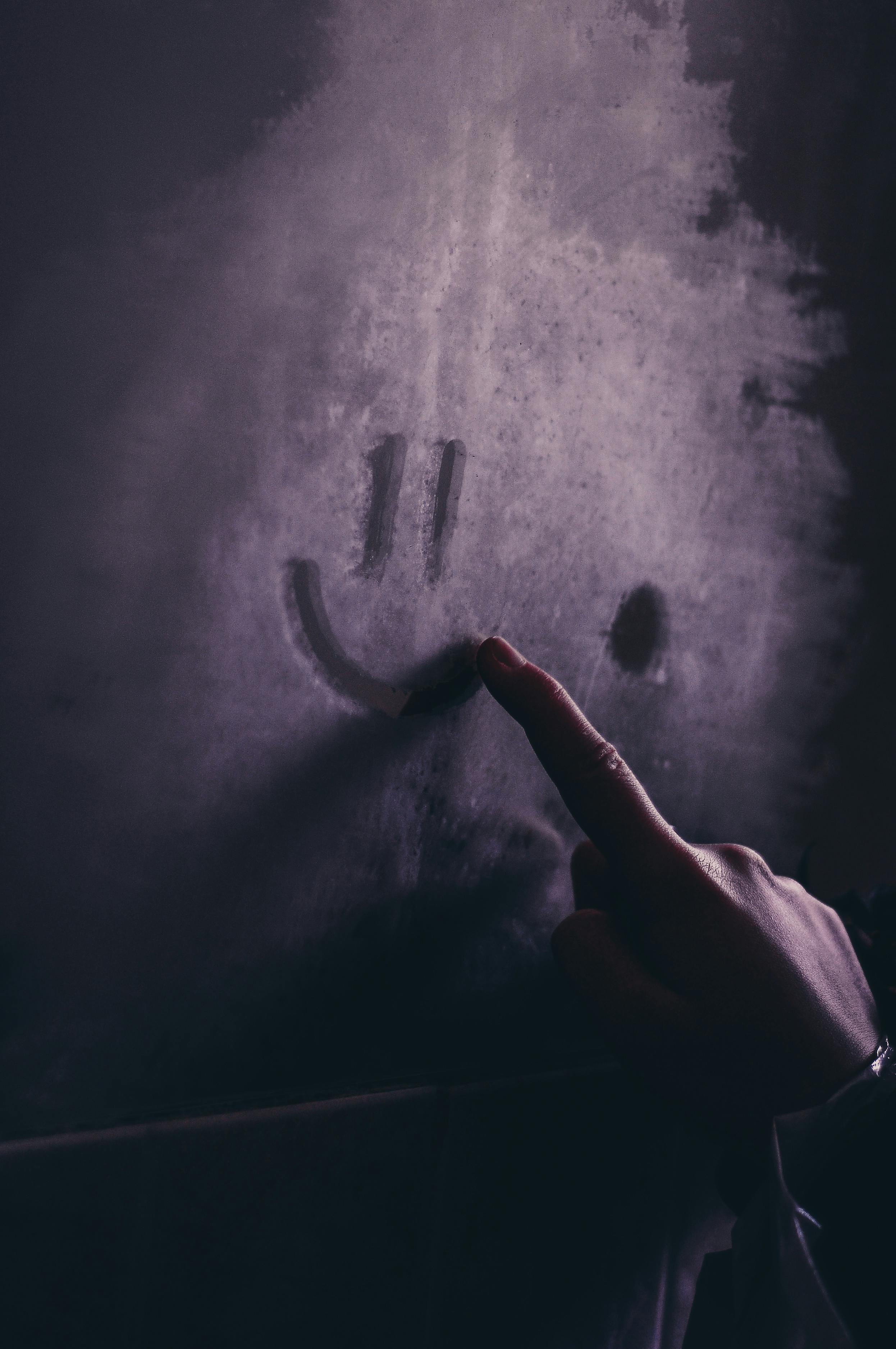 Hand Drawing a Smiley Face on a Dusty Glass · Free Stock Photo