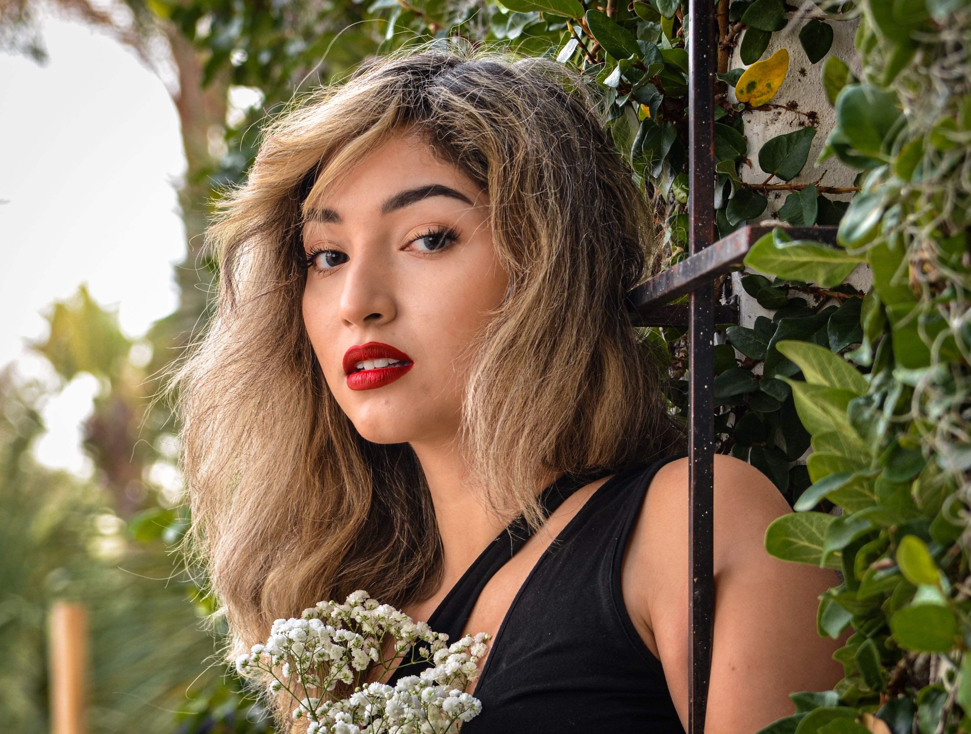 Woman in Black Tank Top Posing the Beside Green Plants · Free Stock Photo