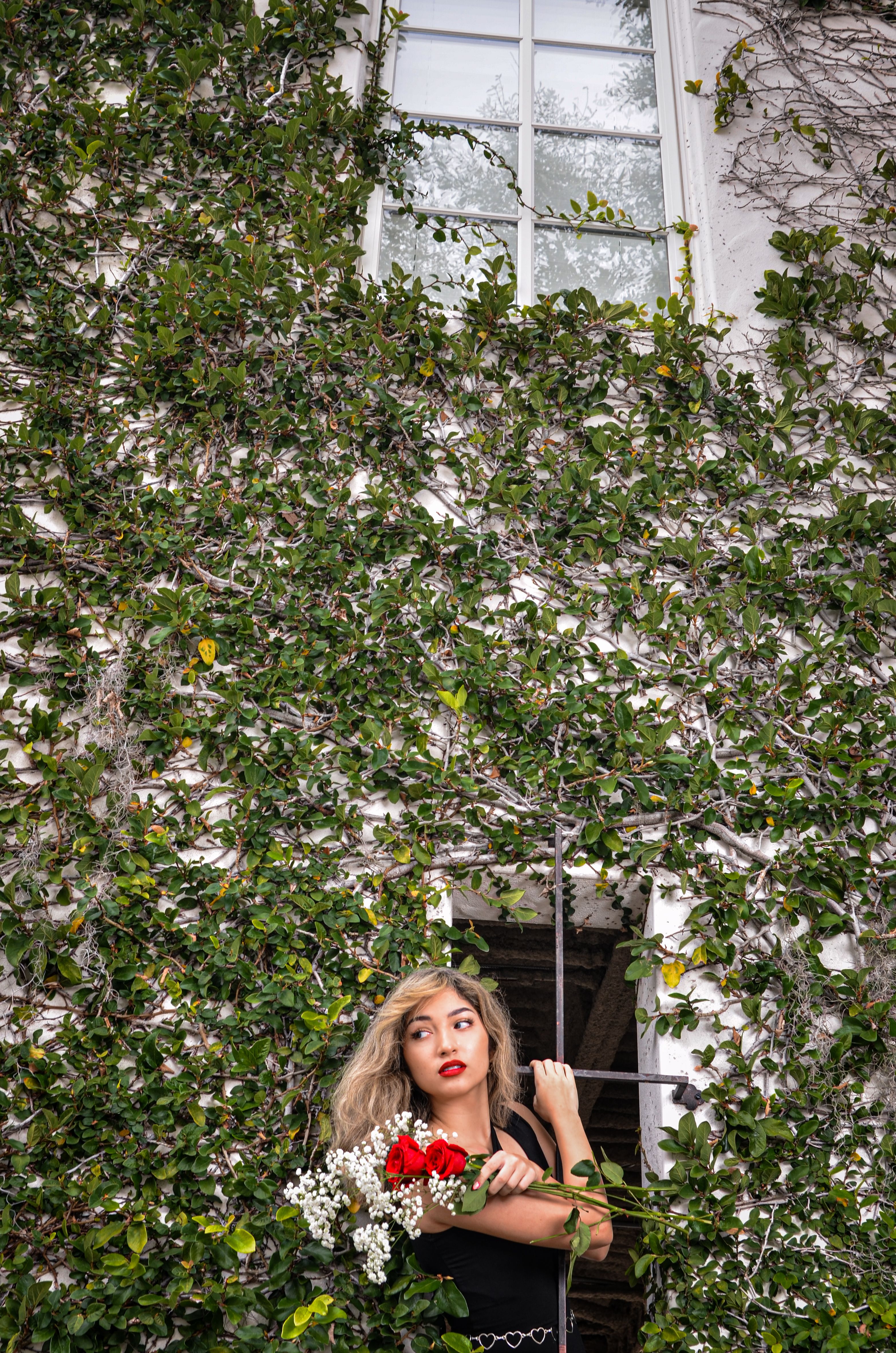 Photograph of a Woman Outside a Window with Green Leaves · Free Stock Photo