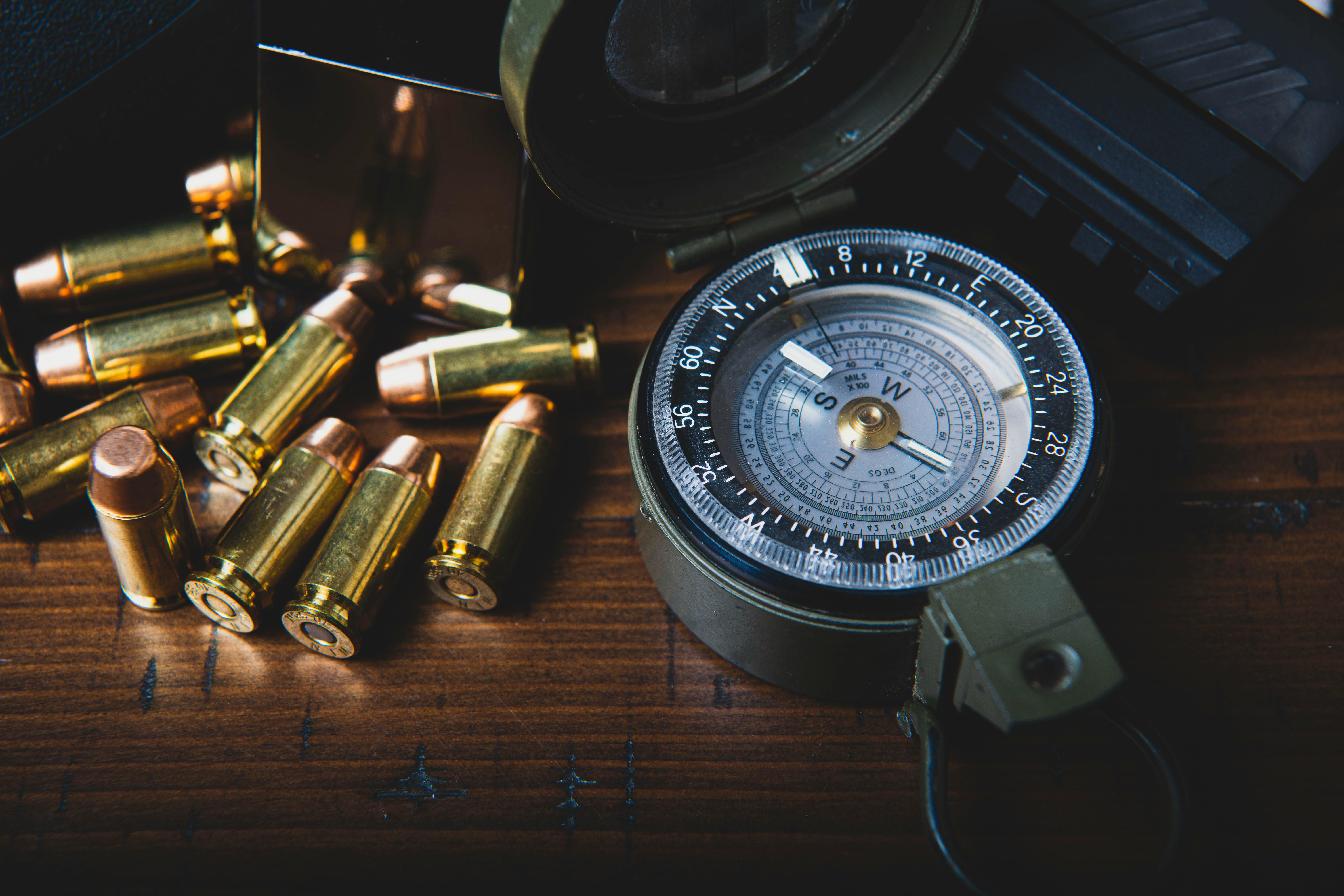 Compass and Bullets on Wooden Surface · Free Stock Photo
