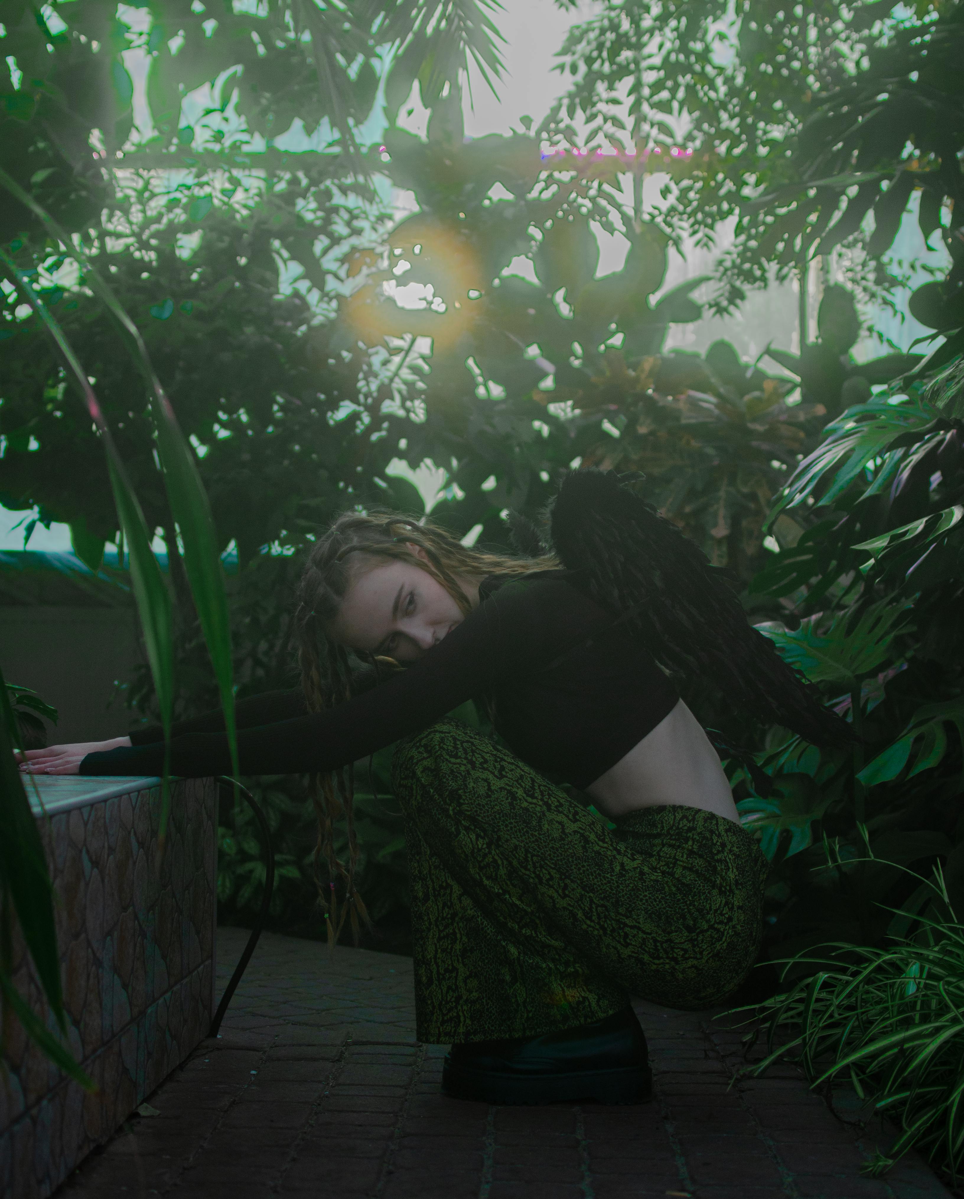 Woman with Dreadlocks with Wings Crouching in Botanical Garden · Free ...