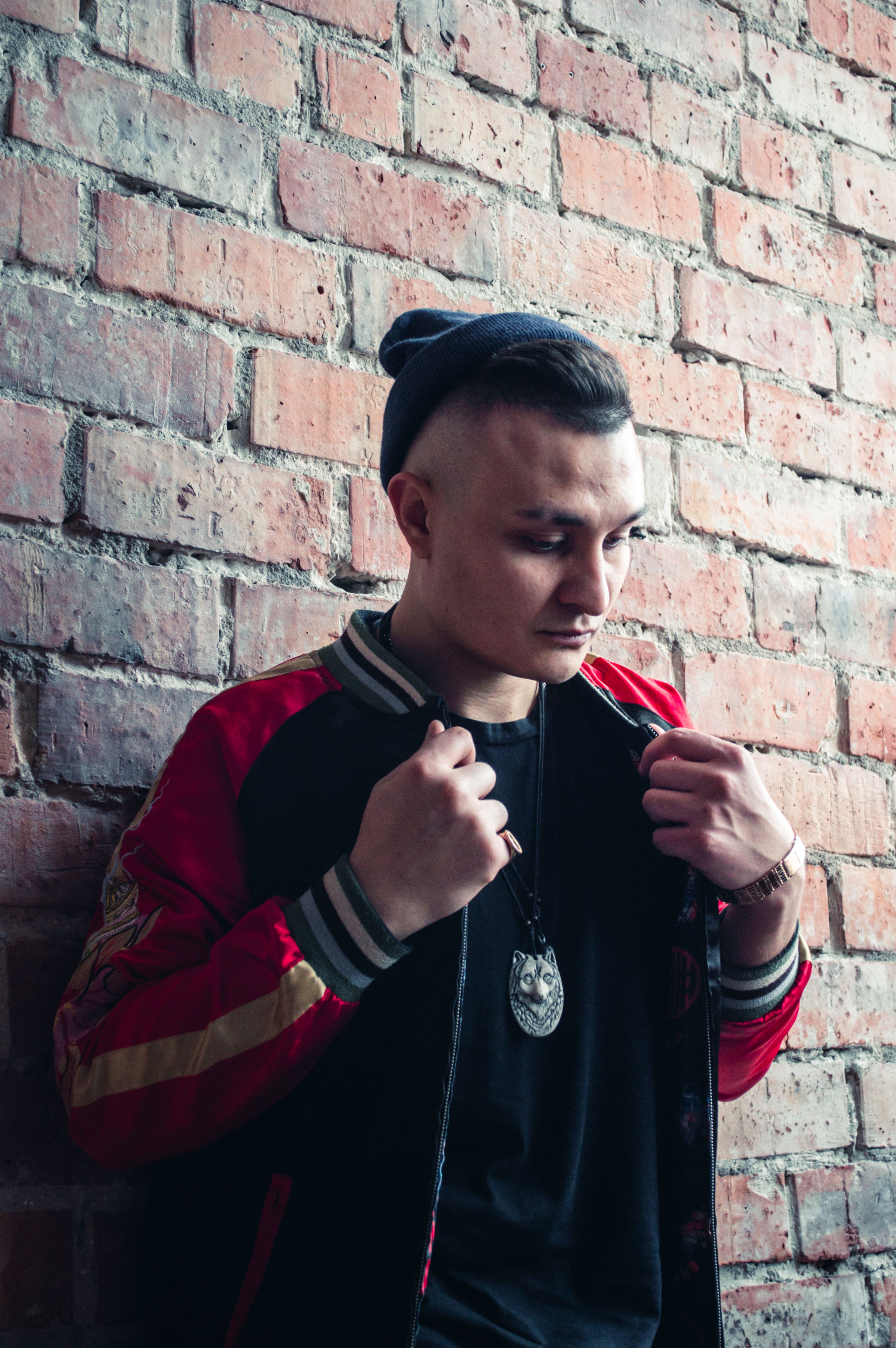 Man Holding His Jacket Leaning on the Brick Wall · Free Stock Photo