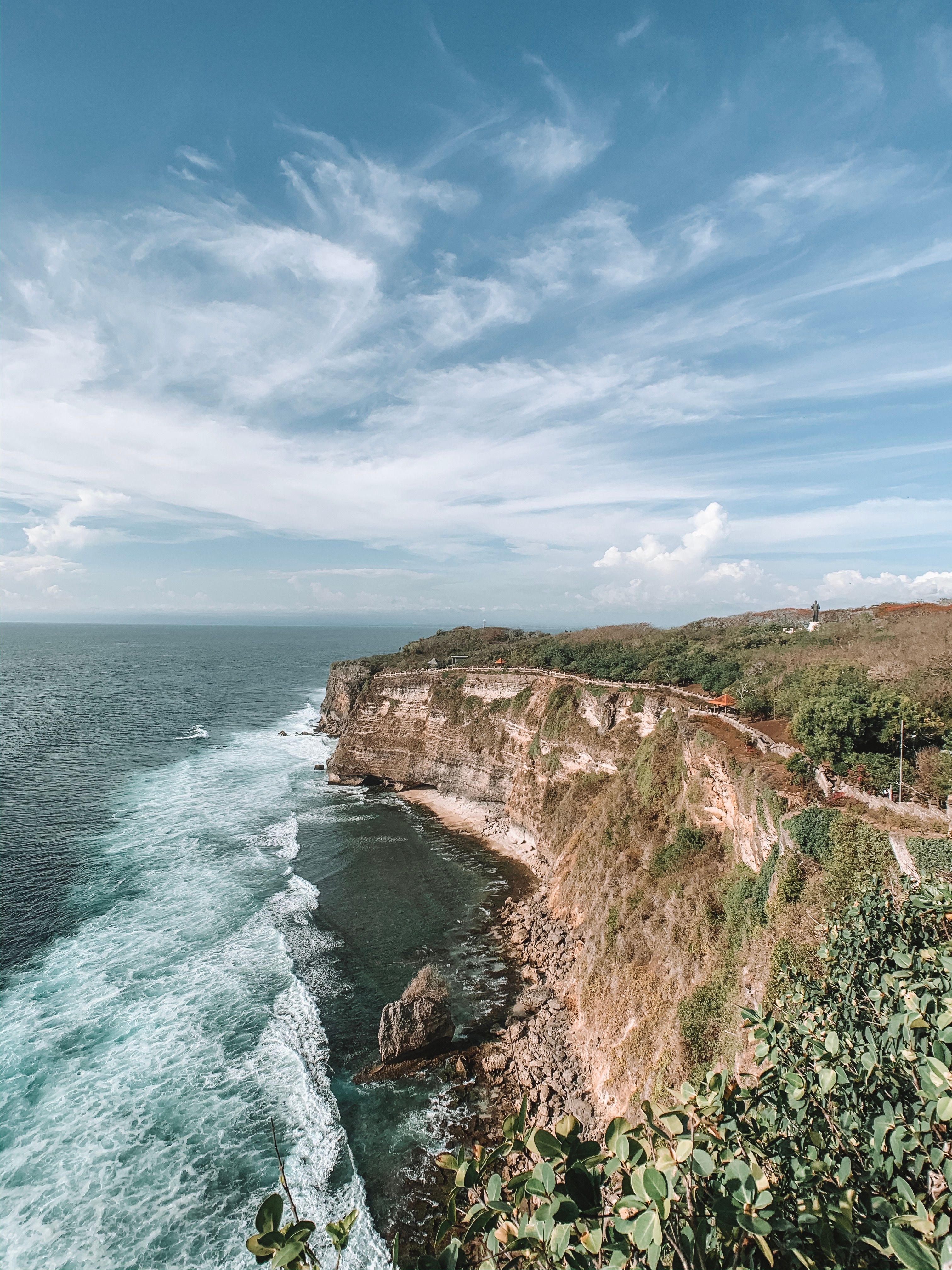 Shoreline Near a Green Cliff · Free Stock Photo