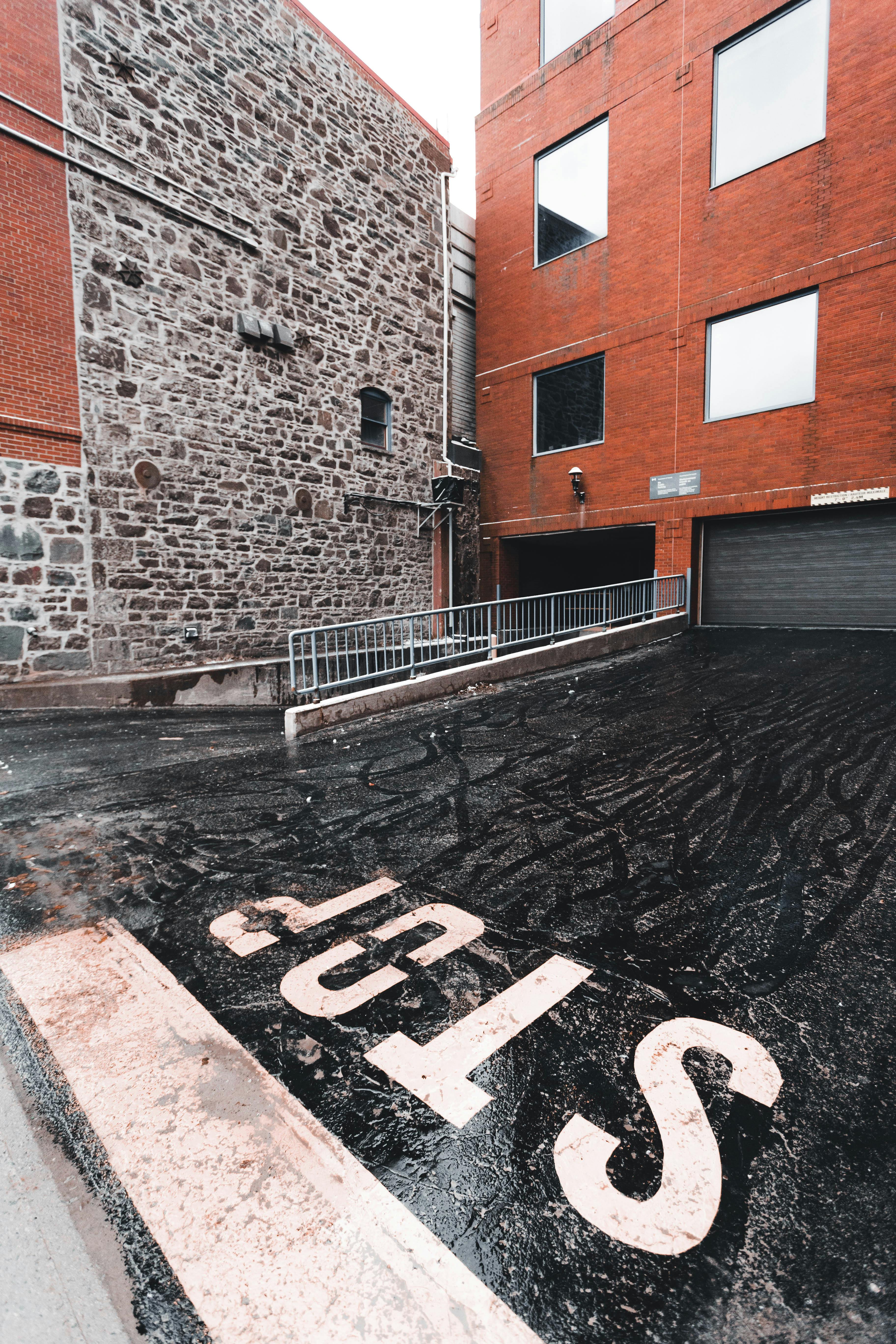 A Stop Sign on Parking Area of a Brown Building · Free Stock Photo