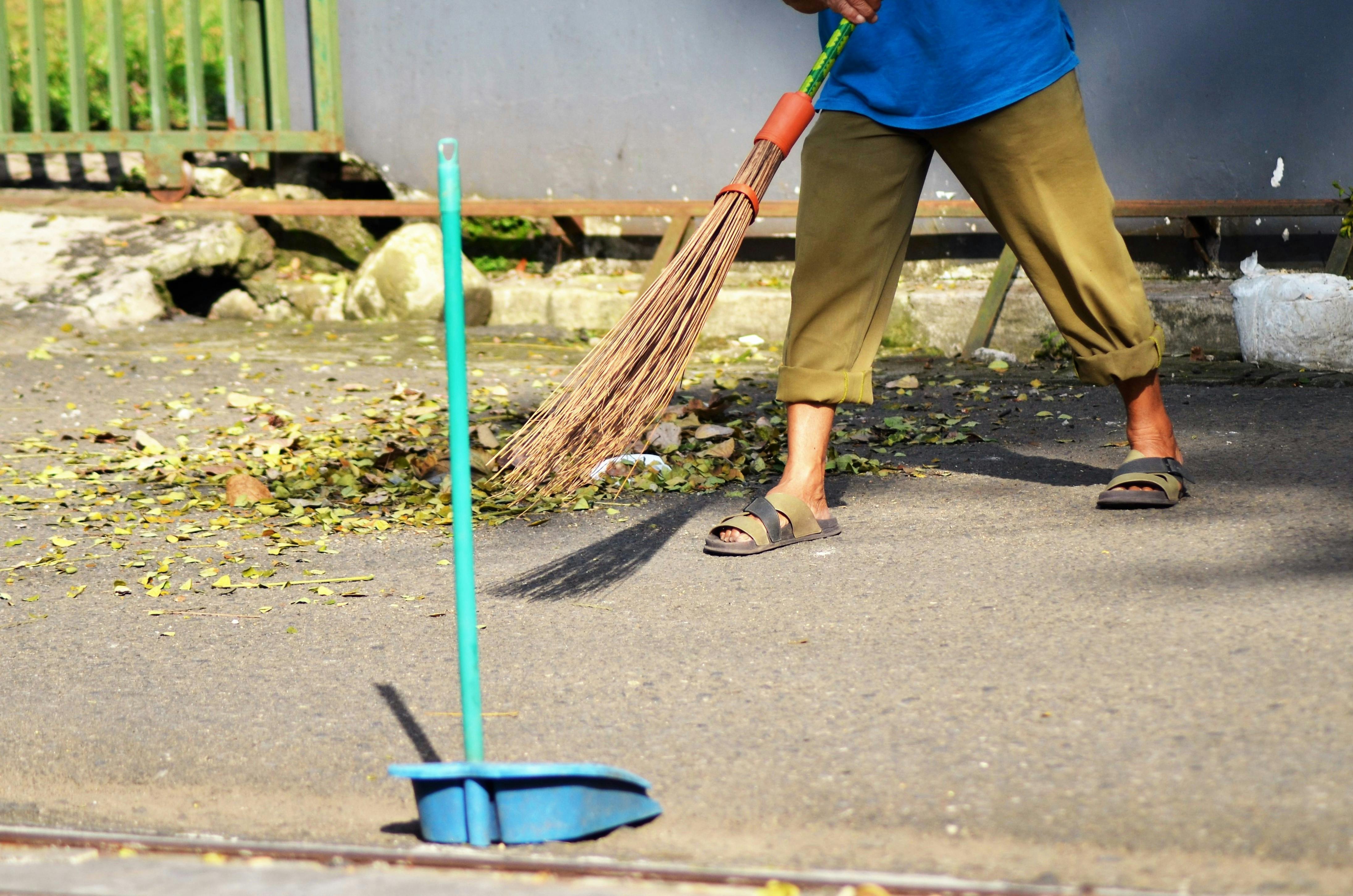 Low Section of a Person Sweeping Leaves · Free Stock Photo