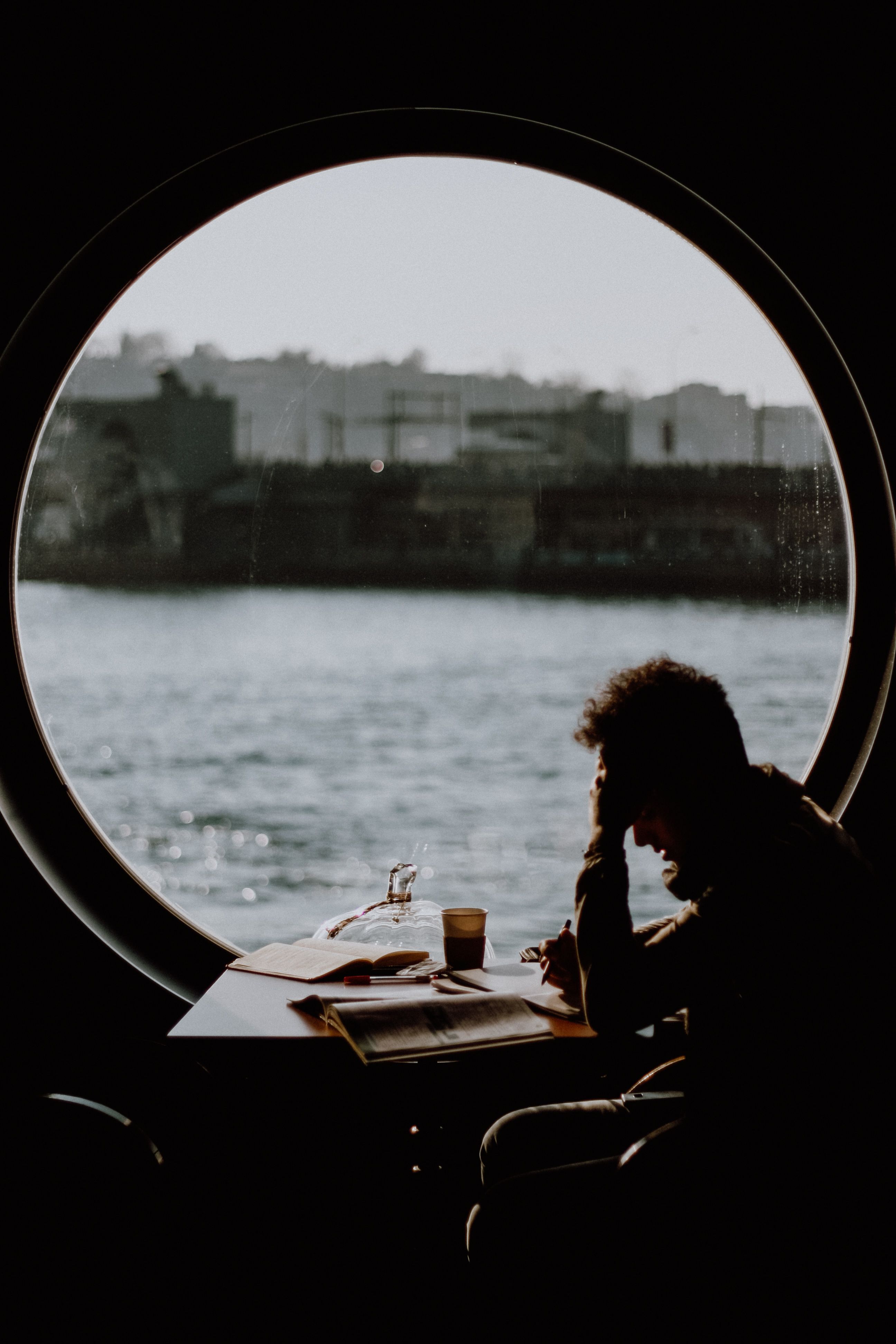 Silhouette of a Man Sitting By a Round Window in a Boat · Free Stock Photo