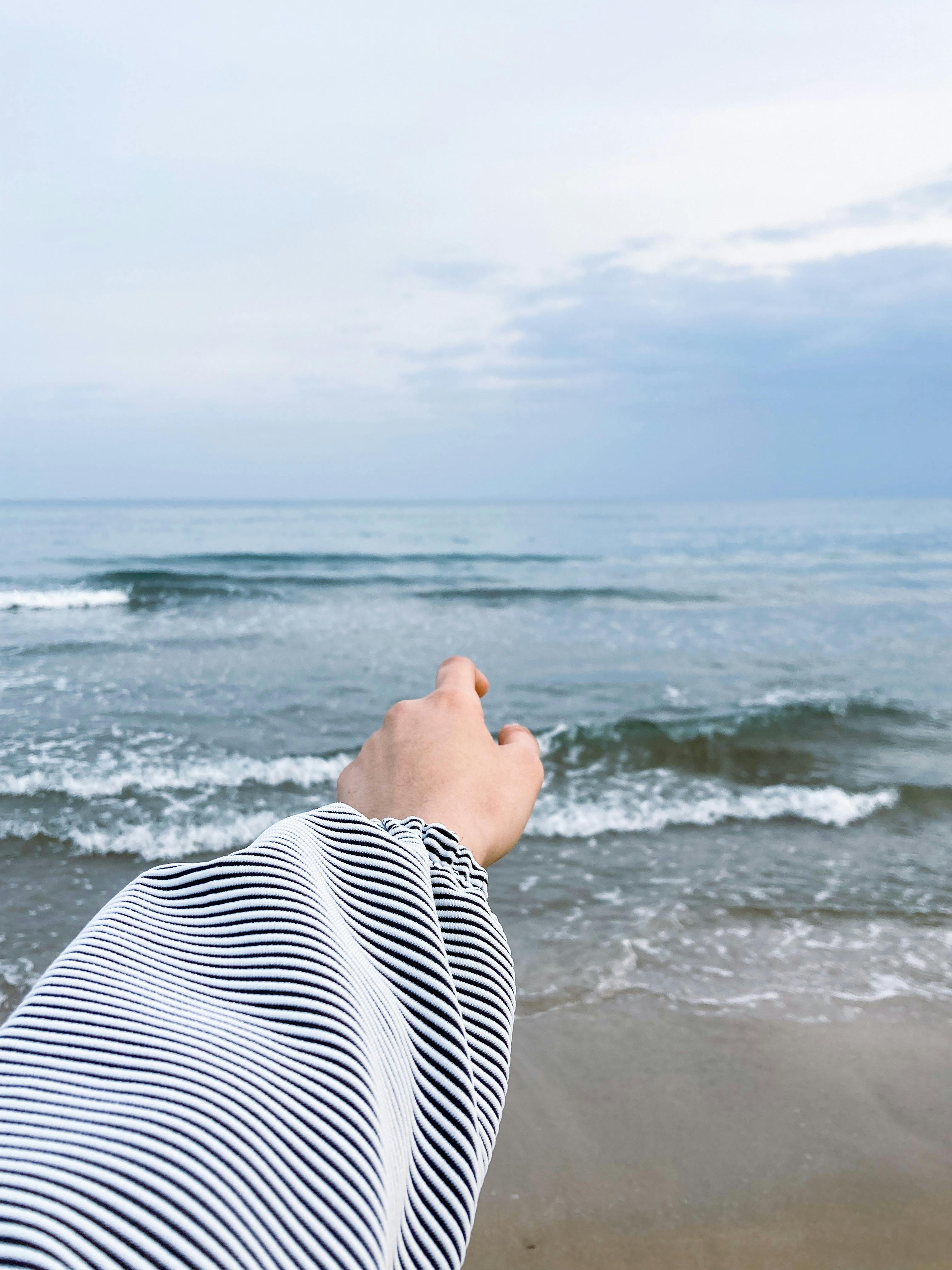 Close up of Hand over Sea · Free Stock Photo
