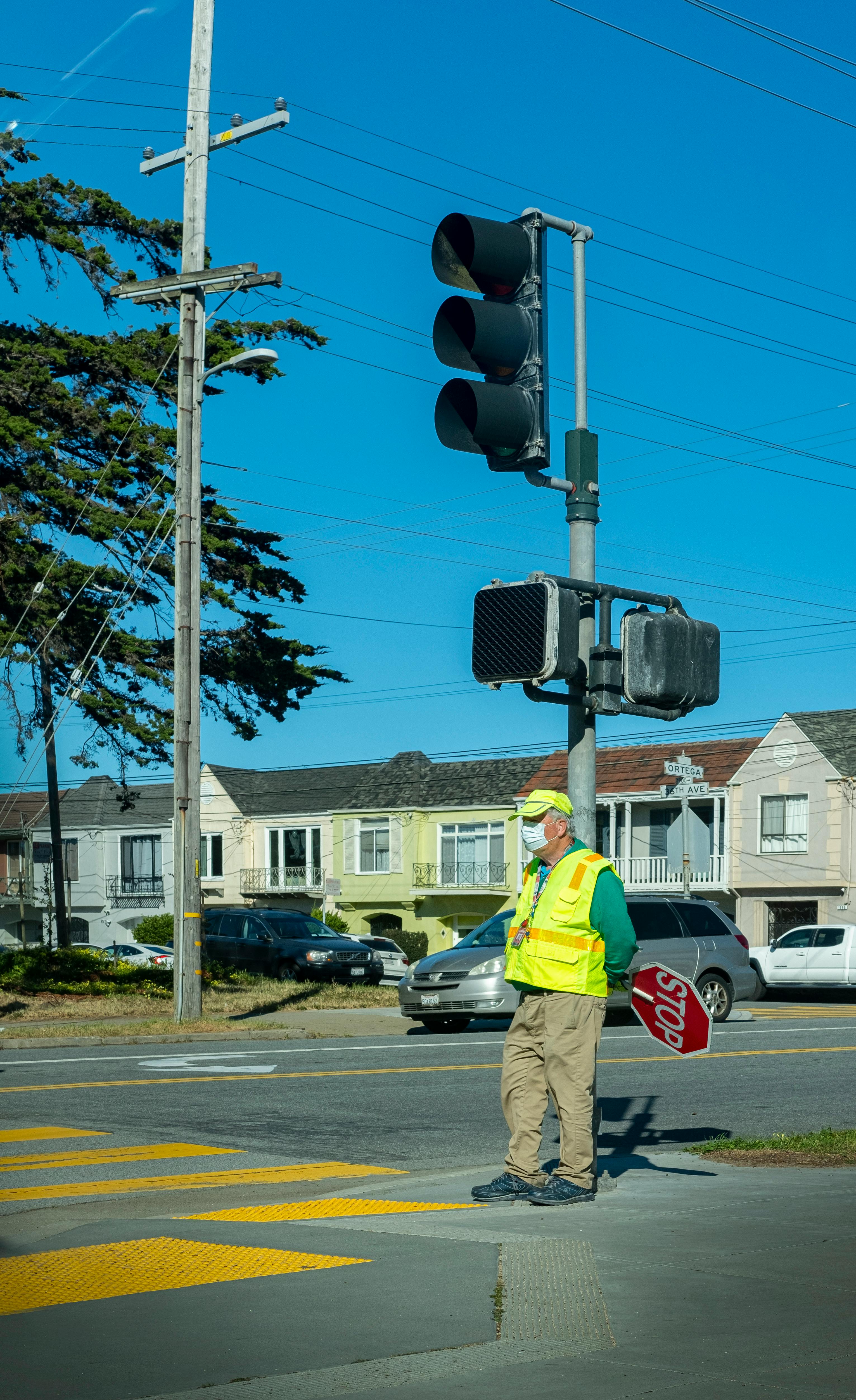 Man in a Safety Vest Holding a Stop Sign Standing by a Traffic Light ...