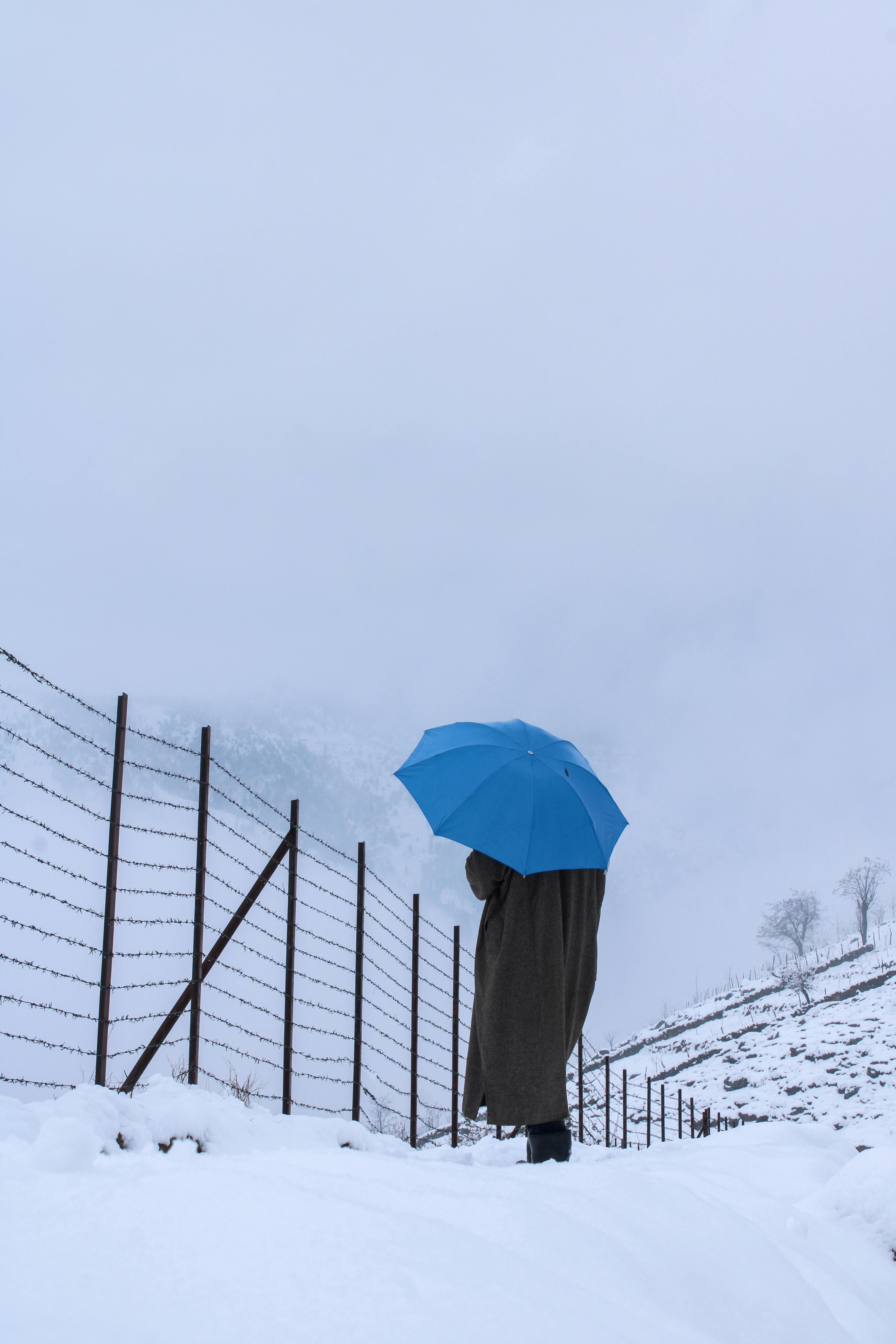 Person Walking on Snow Covered Street with an Umbrella during Night ...