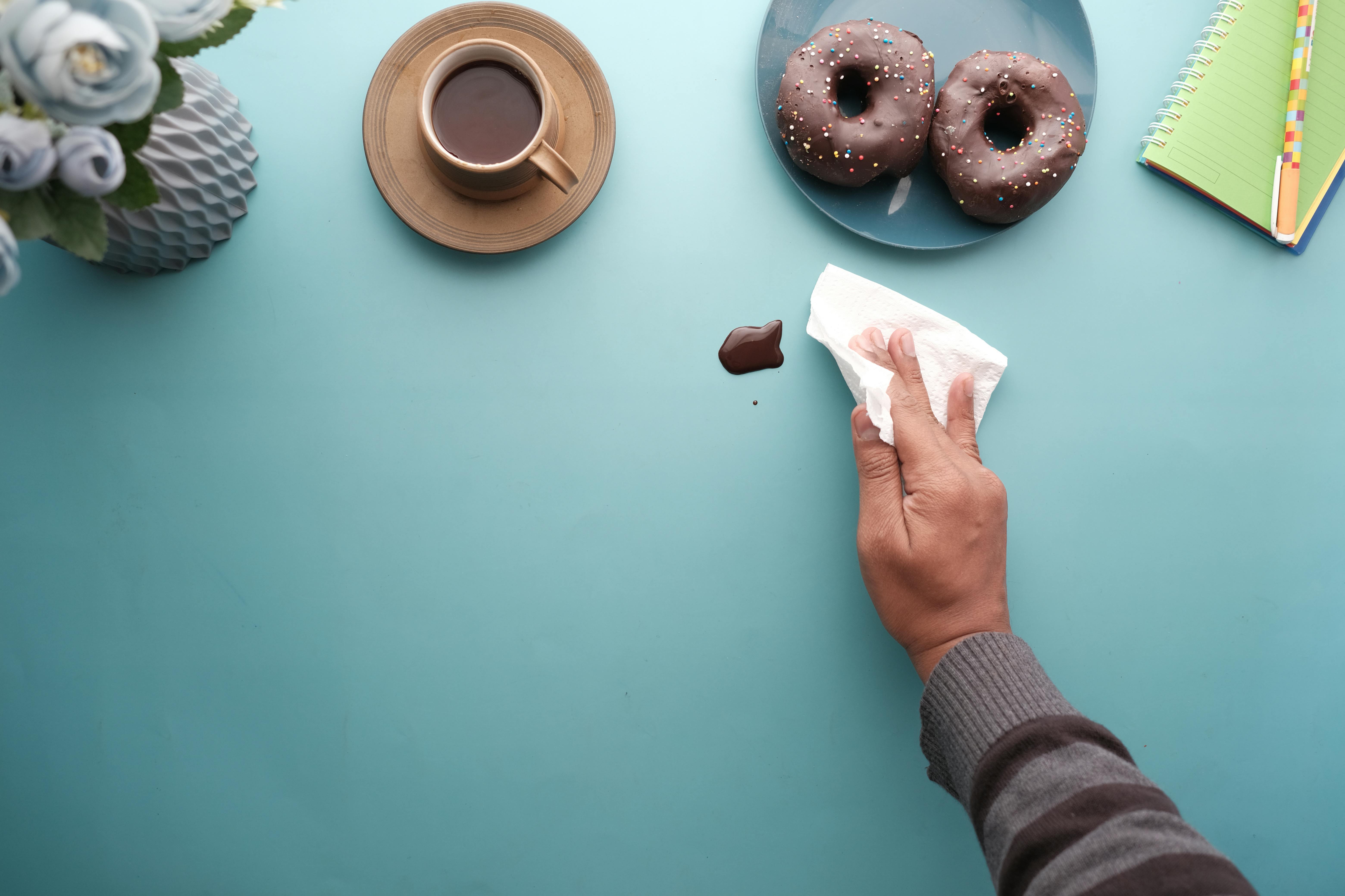 Waiter cleaning Table top while holding a Ceramic Cup · Free Stock Photo