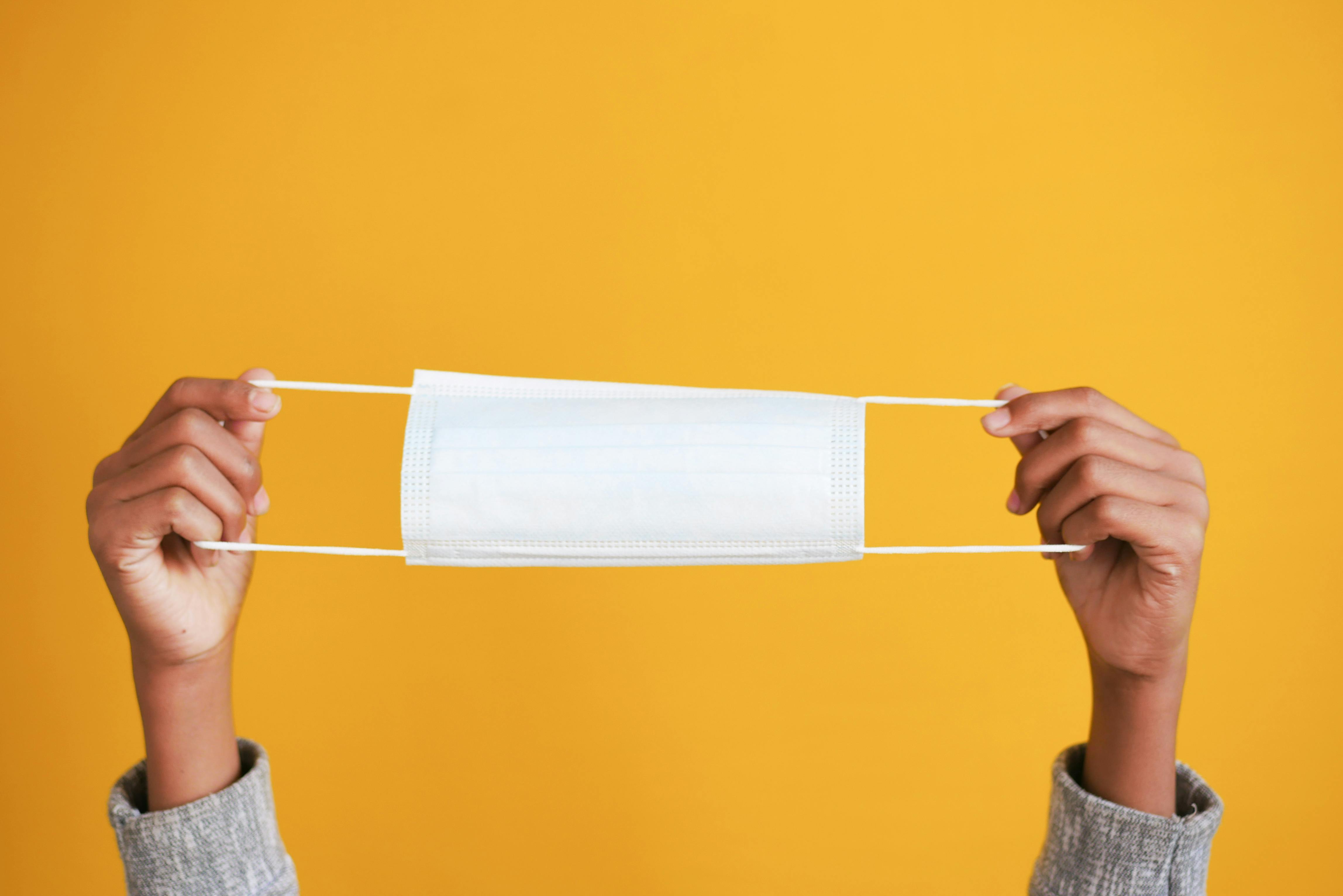 A Person Holding White Face Mask · Free Stock Photo
