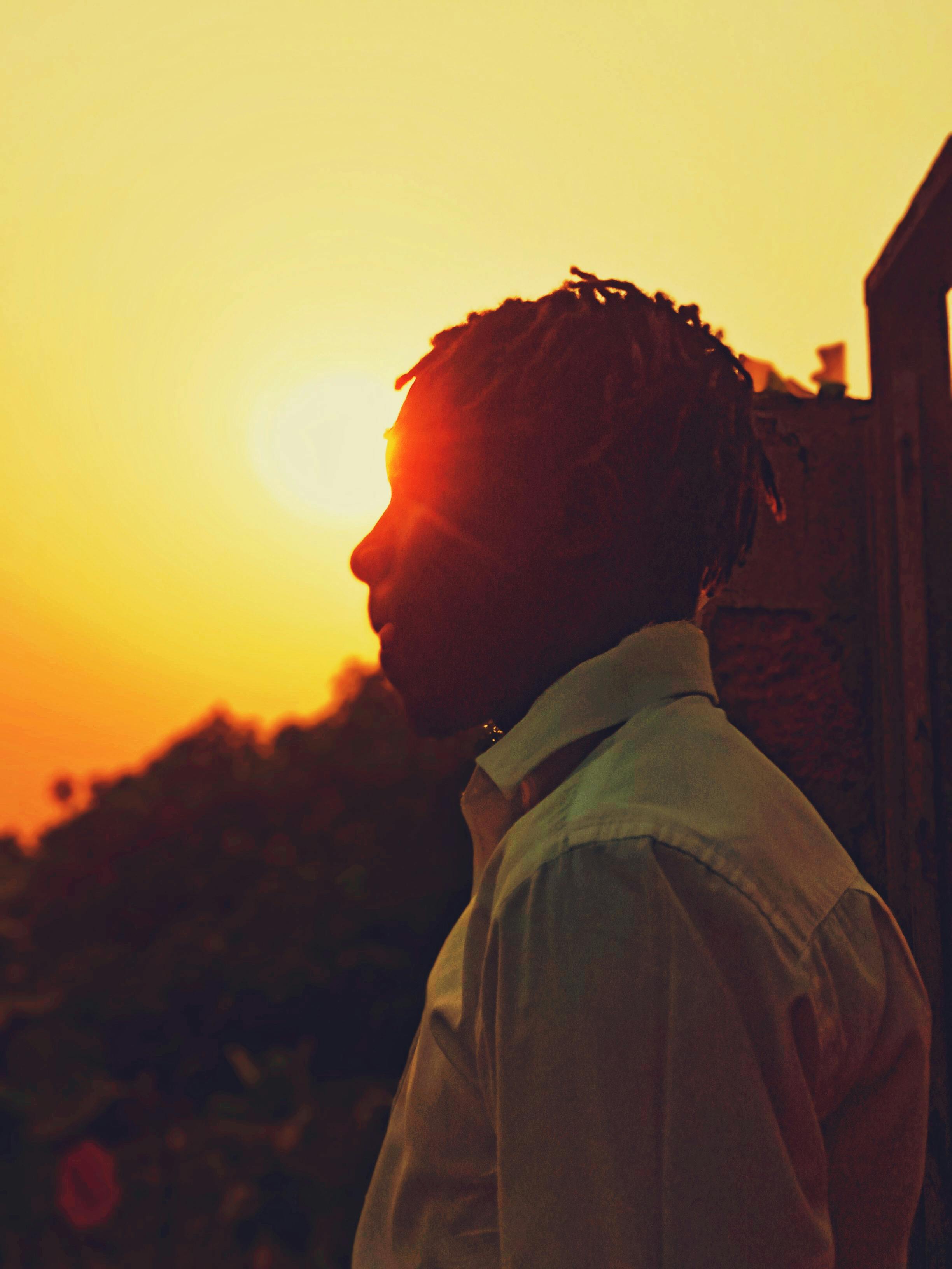 Man Sitting on Edge Facing Sunset · Free Stock Photo
