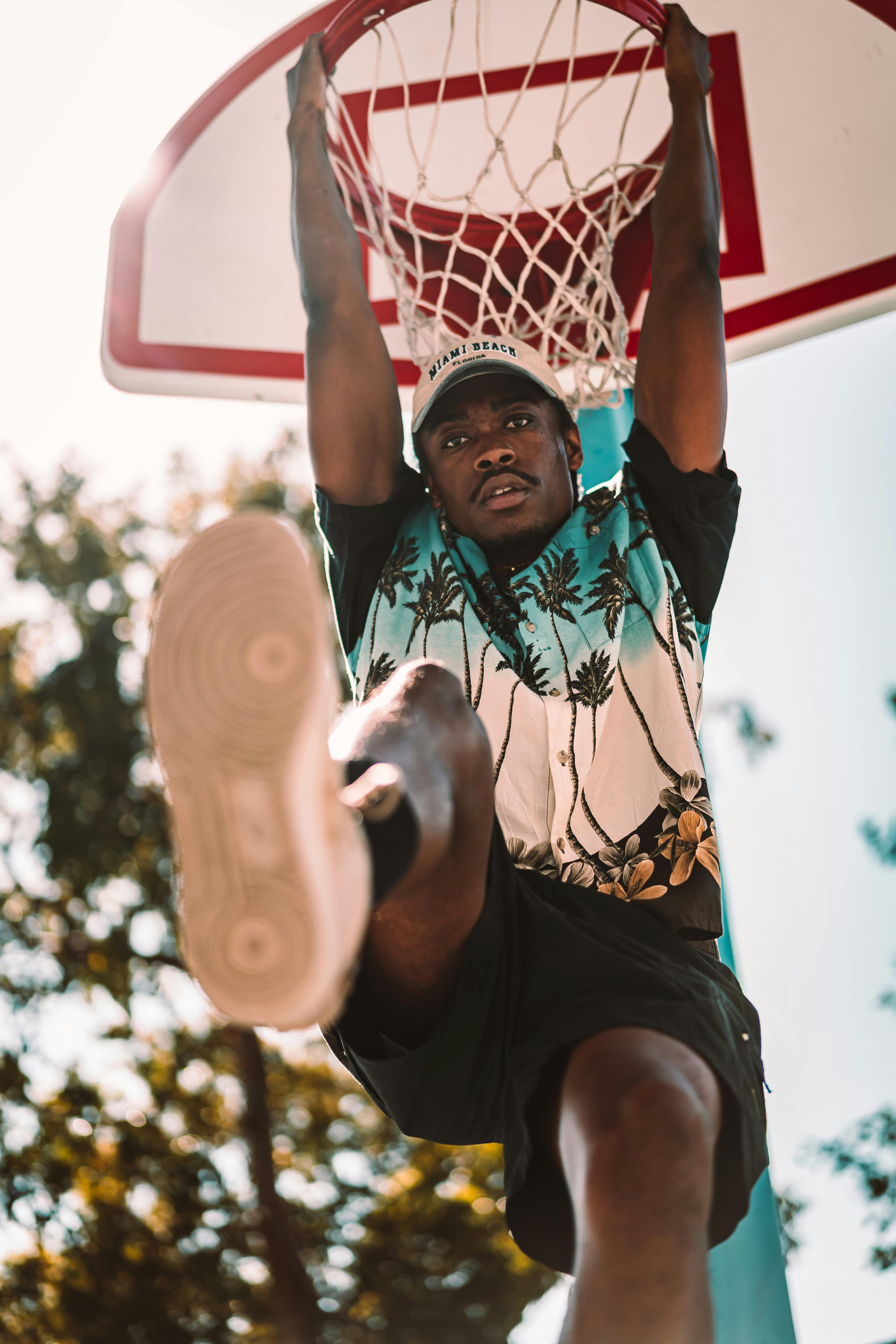 Man Swinging From Basketball Hoop · Free Stock Photo