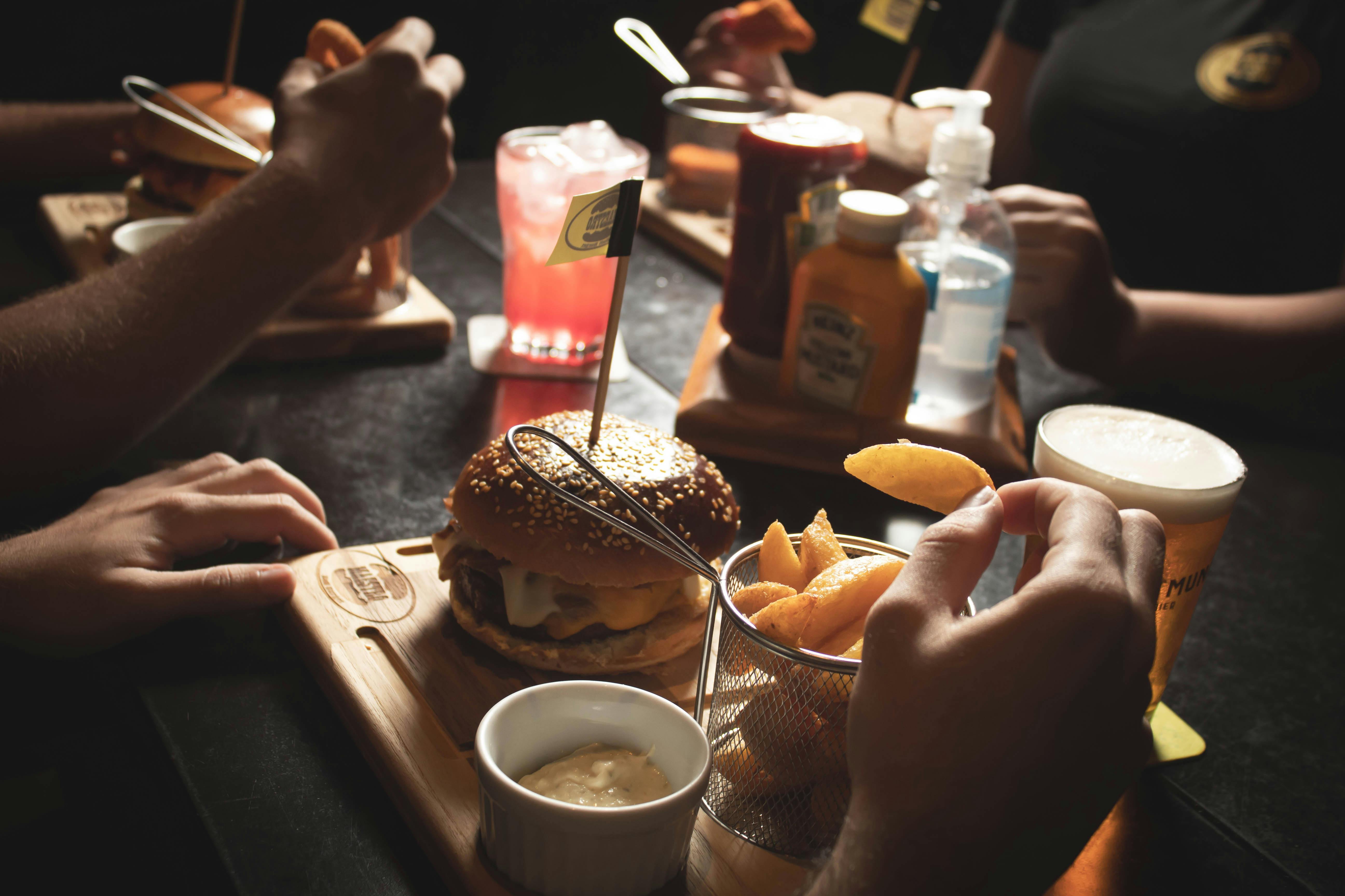 People Eating Burgers and French Fries on Dining Table on a Restaurant ...
