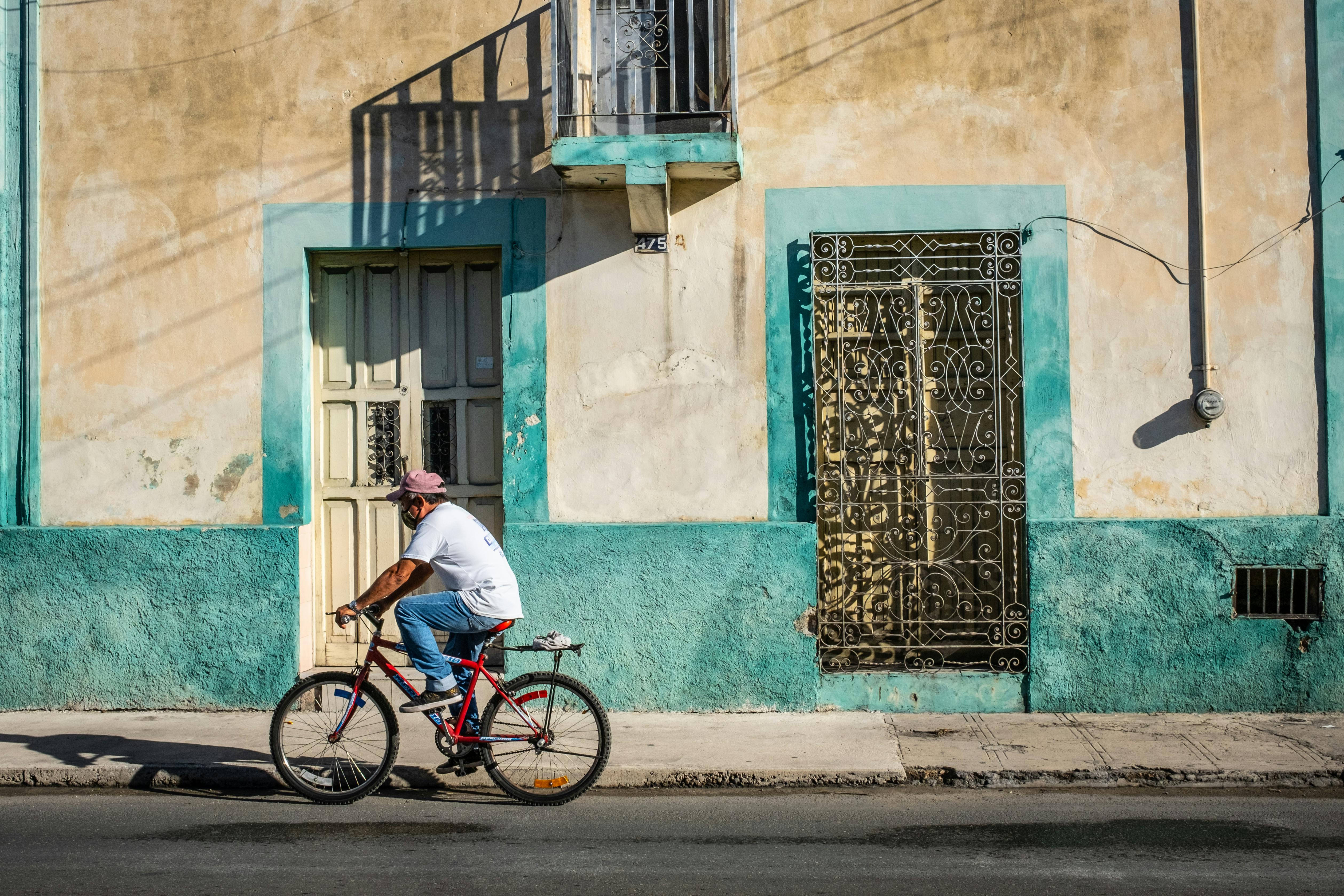 Man Riding a Bicycle in Front of a Building · Free Stock Photo
