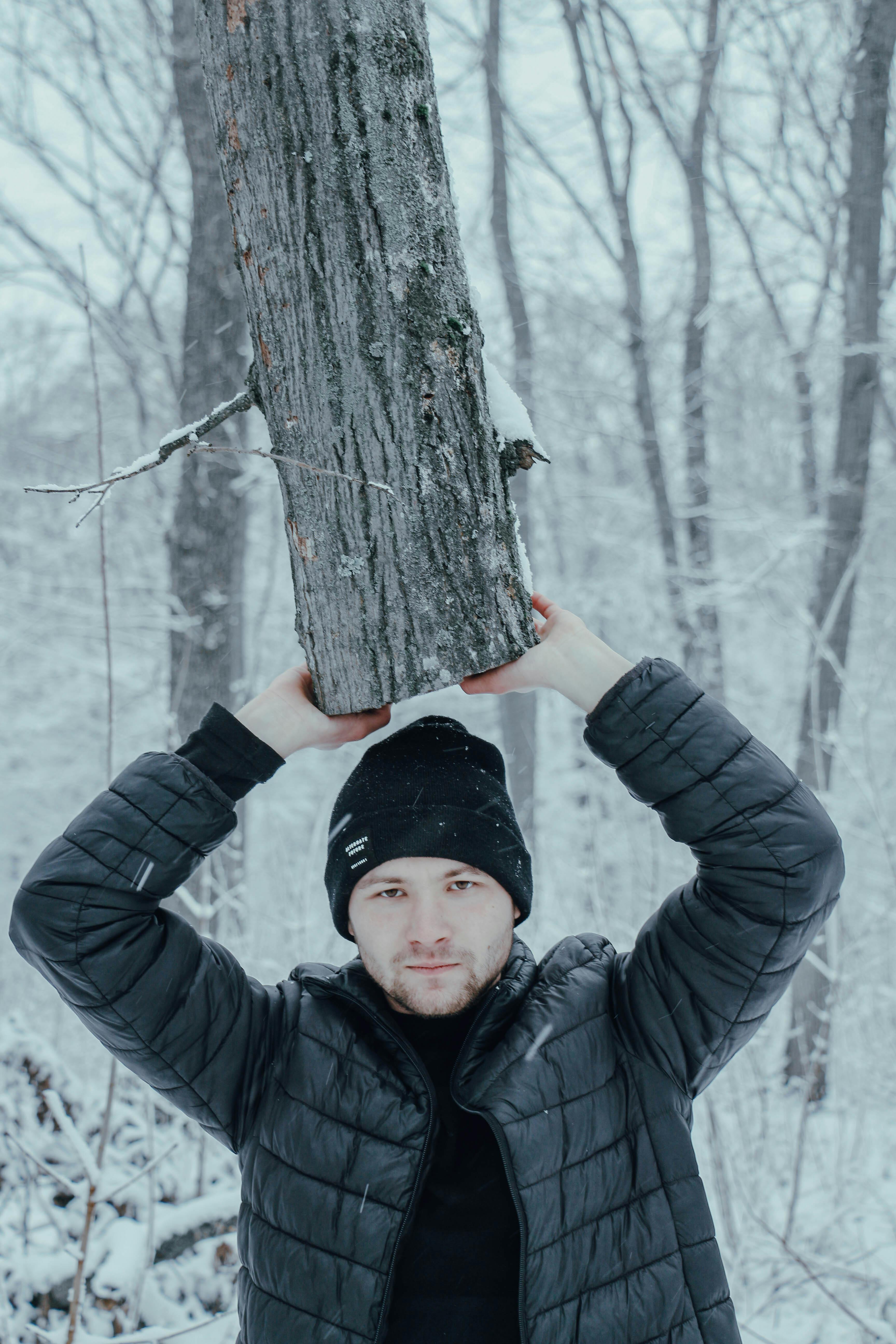 Man Holding Tree Trunk in Winter Forest · Free Stock Photo