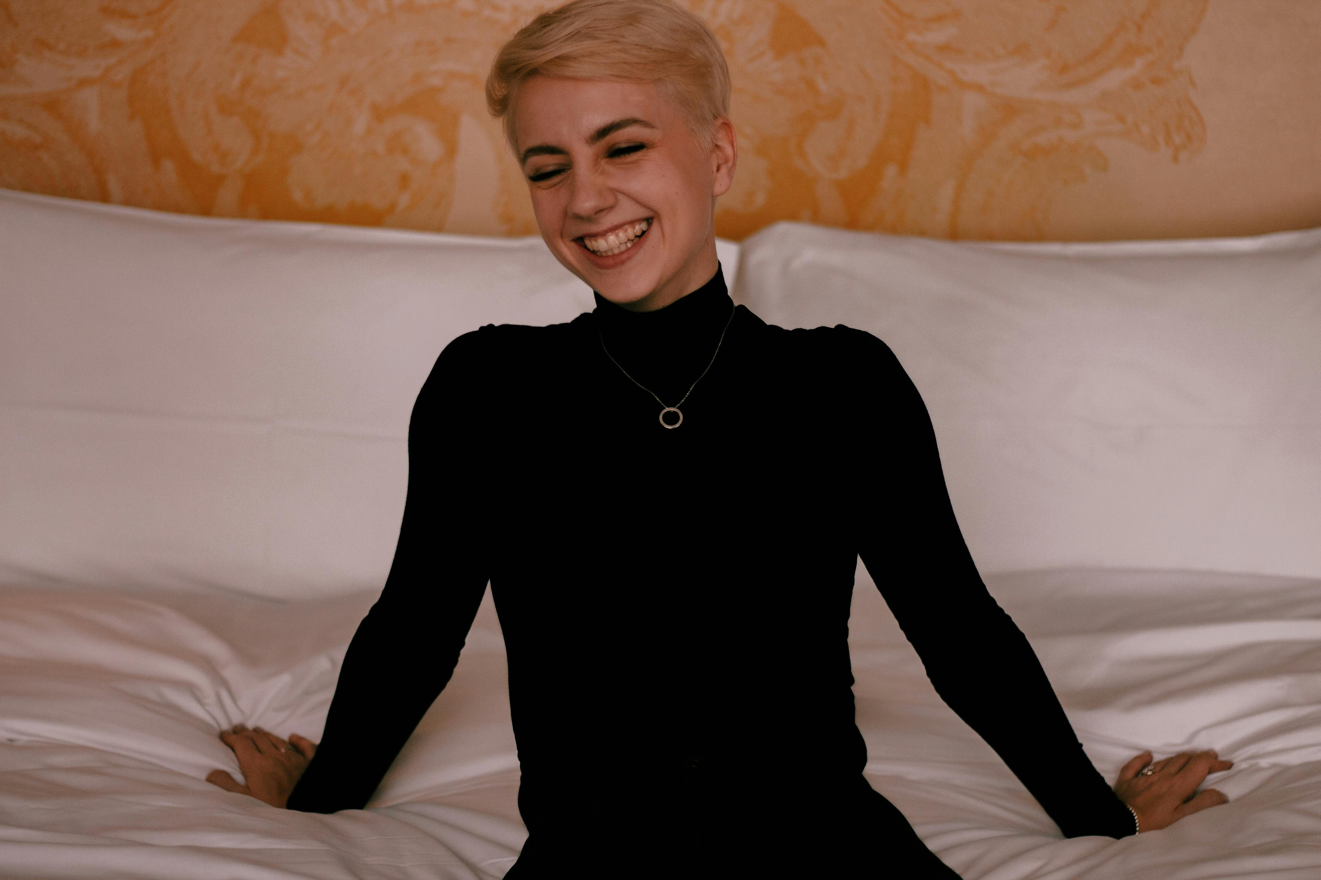 Woman in Black Long Sleeve Shirt Sitting on Bed · Free Stock Photo