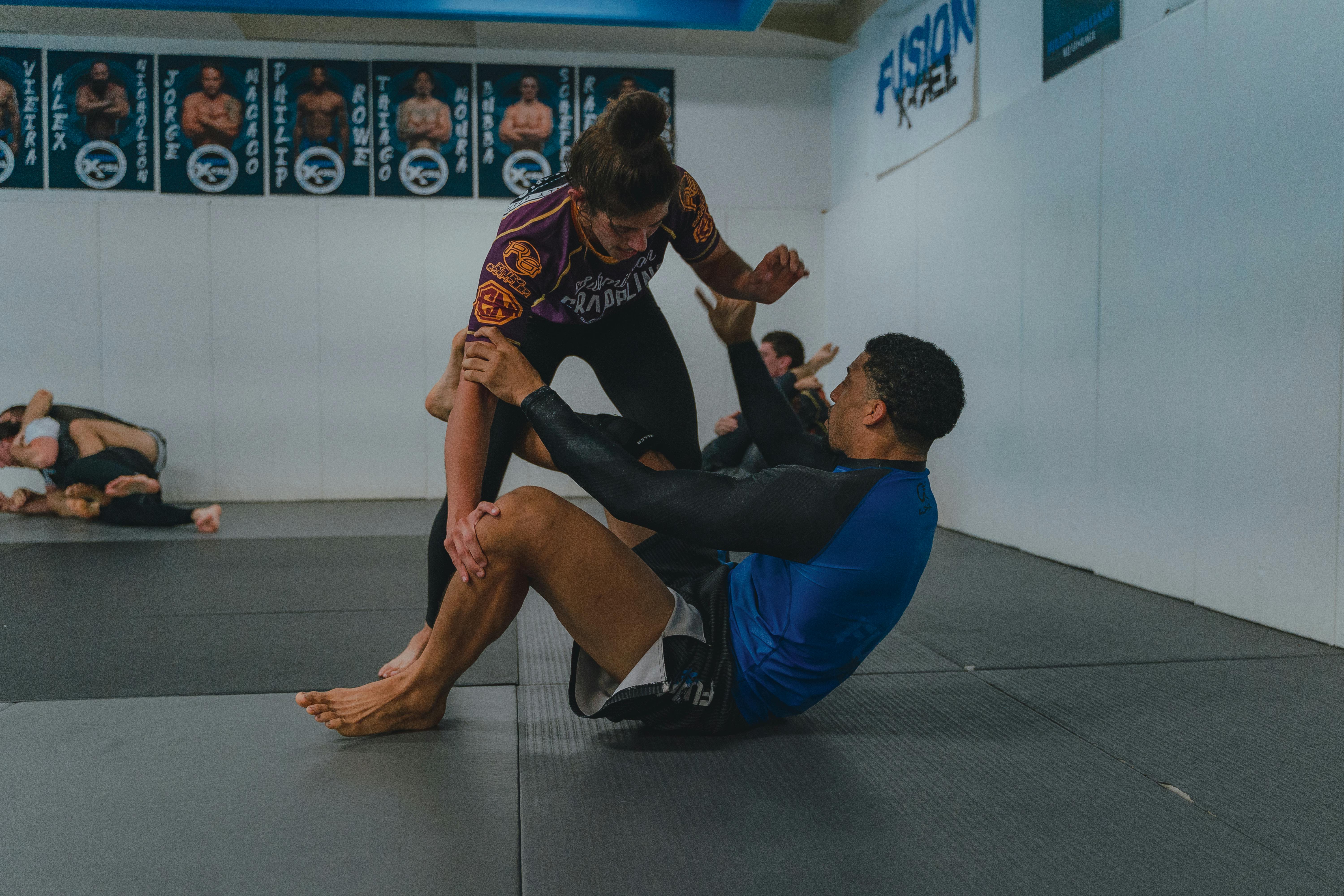 Two People Wrestling on a Gray Mat · Free Stock Photo