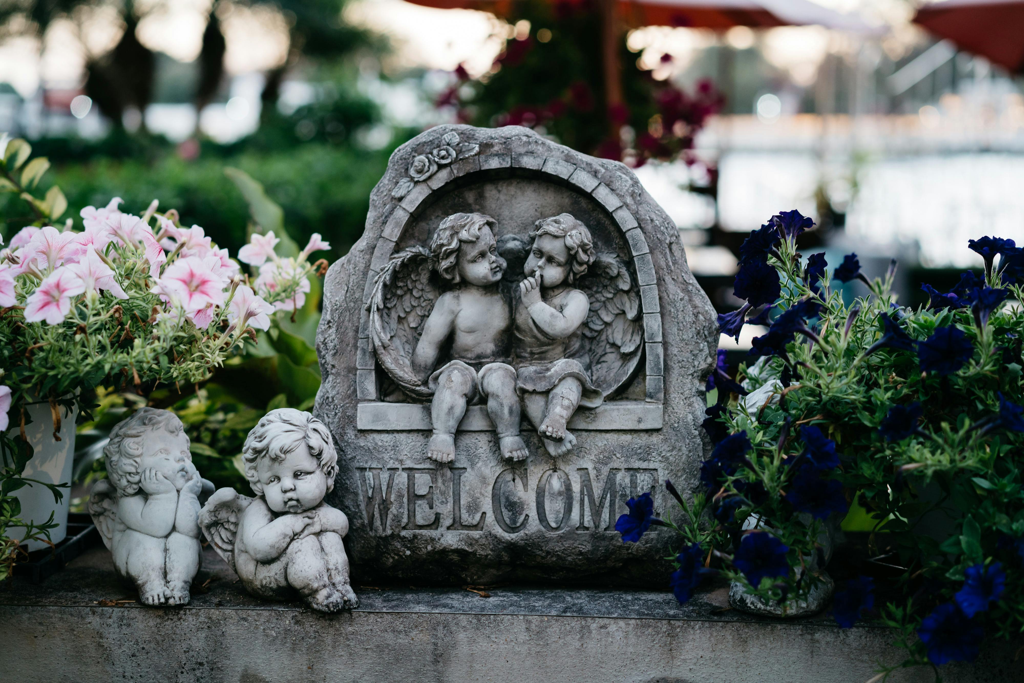 Gray Concrete Angel Statues Near Purple Flowers · Free Stock Photo