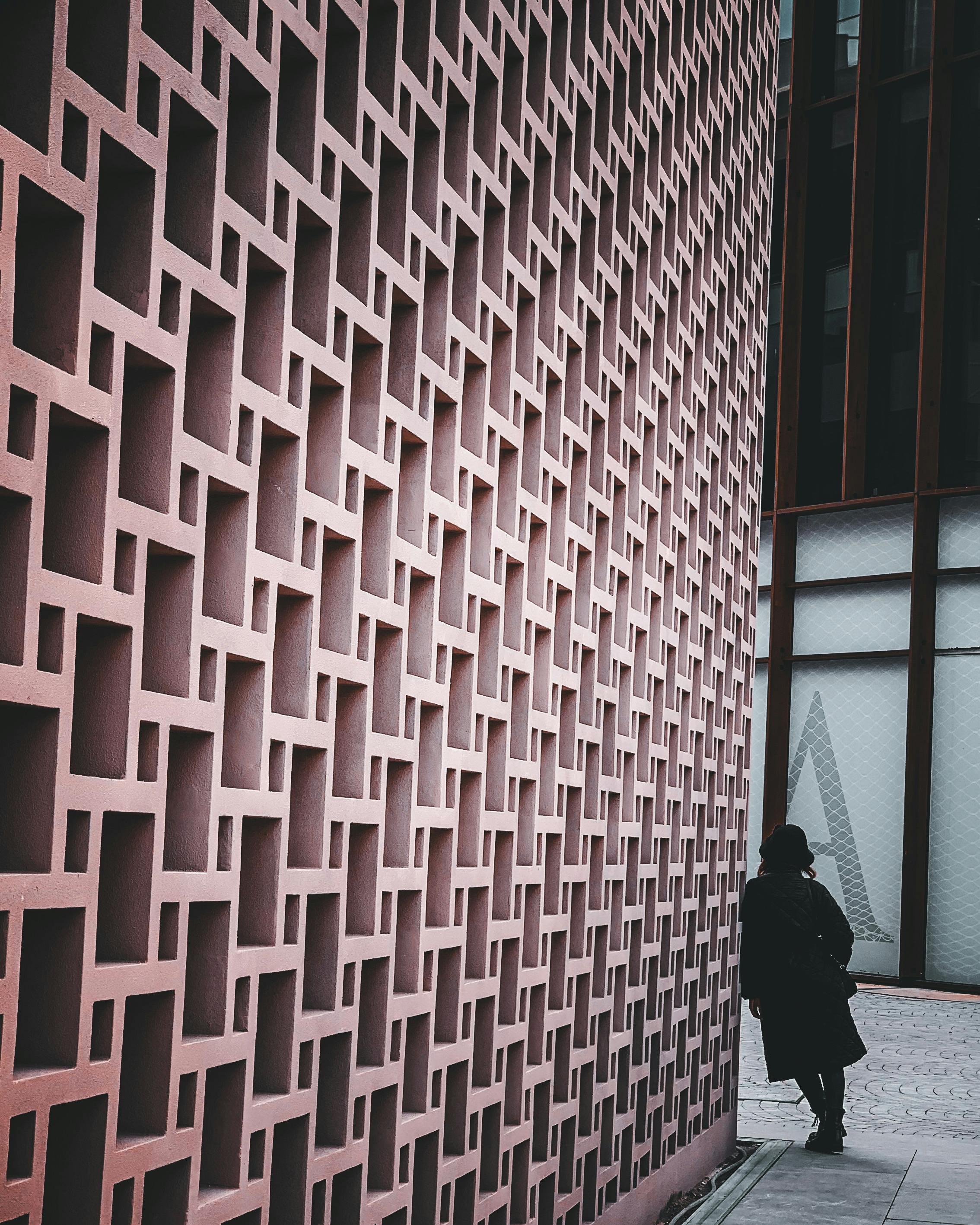 Woman Leaning against Wall with Geometric Pattern · Free Stock Photo