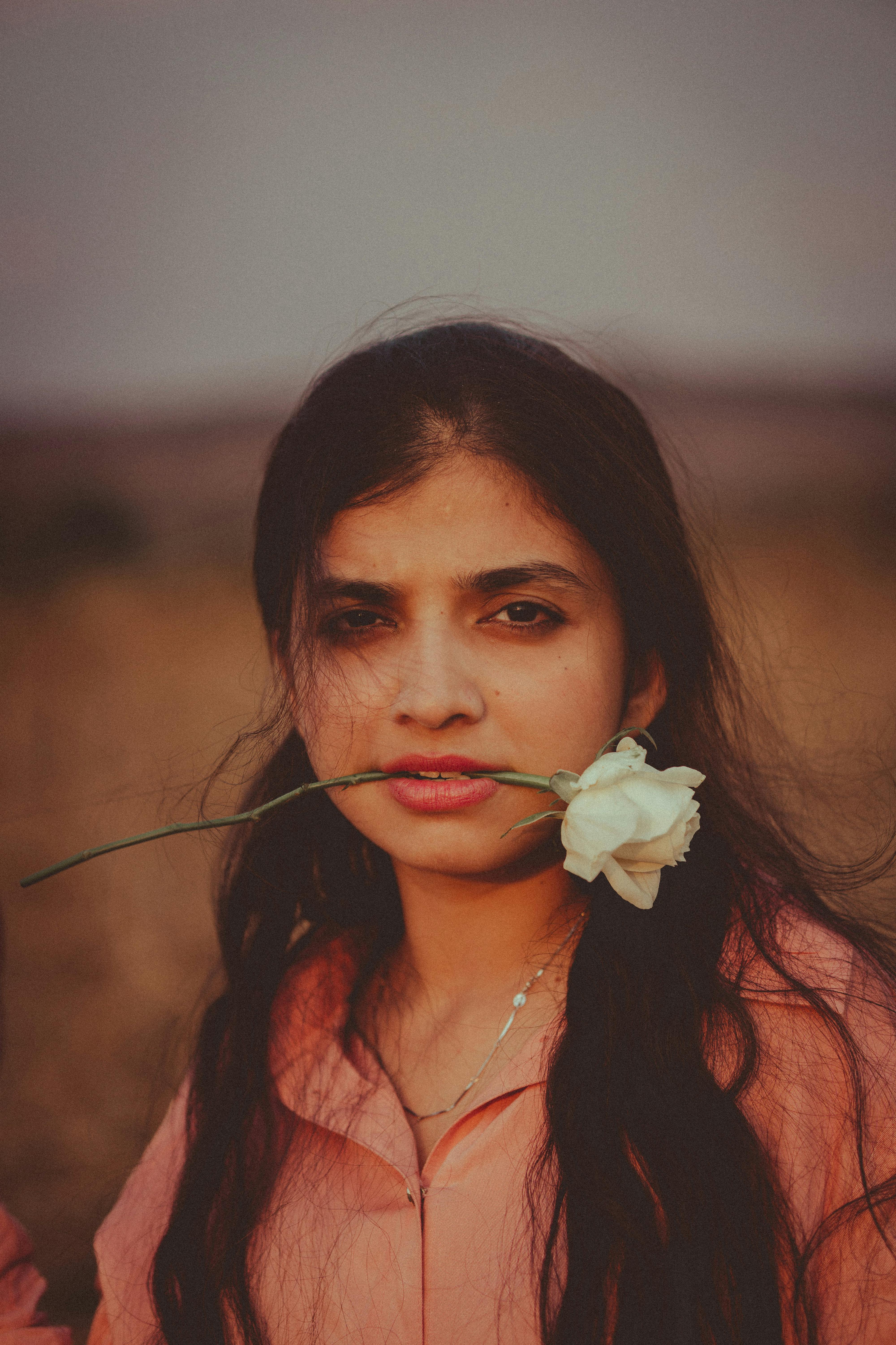 A Woman in a Pink Dress Biting a Rose · Free Stock Photo