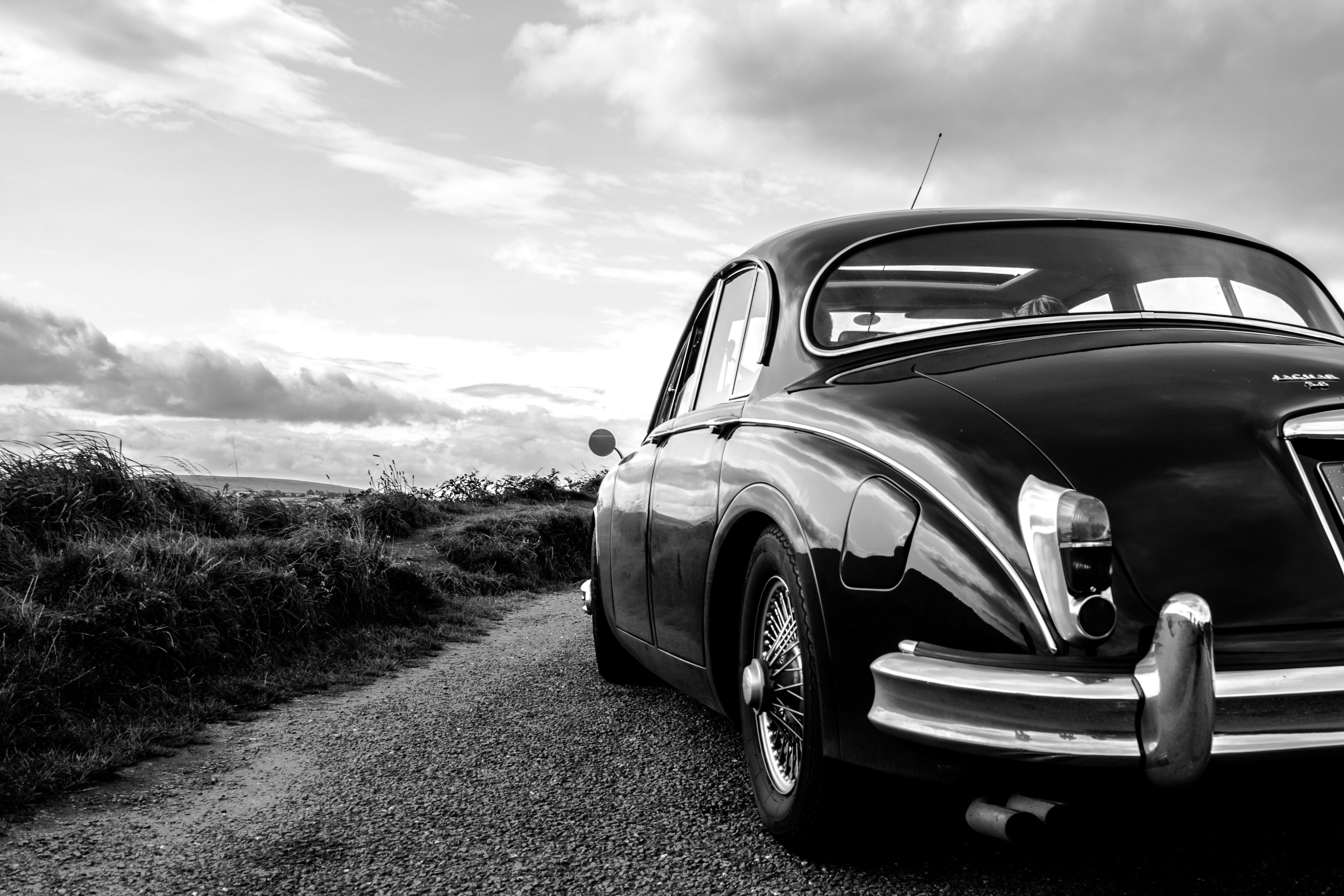 Grayscale Photo of a Vintage Car on the Road · Free Stock Photo