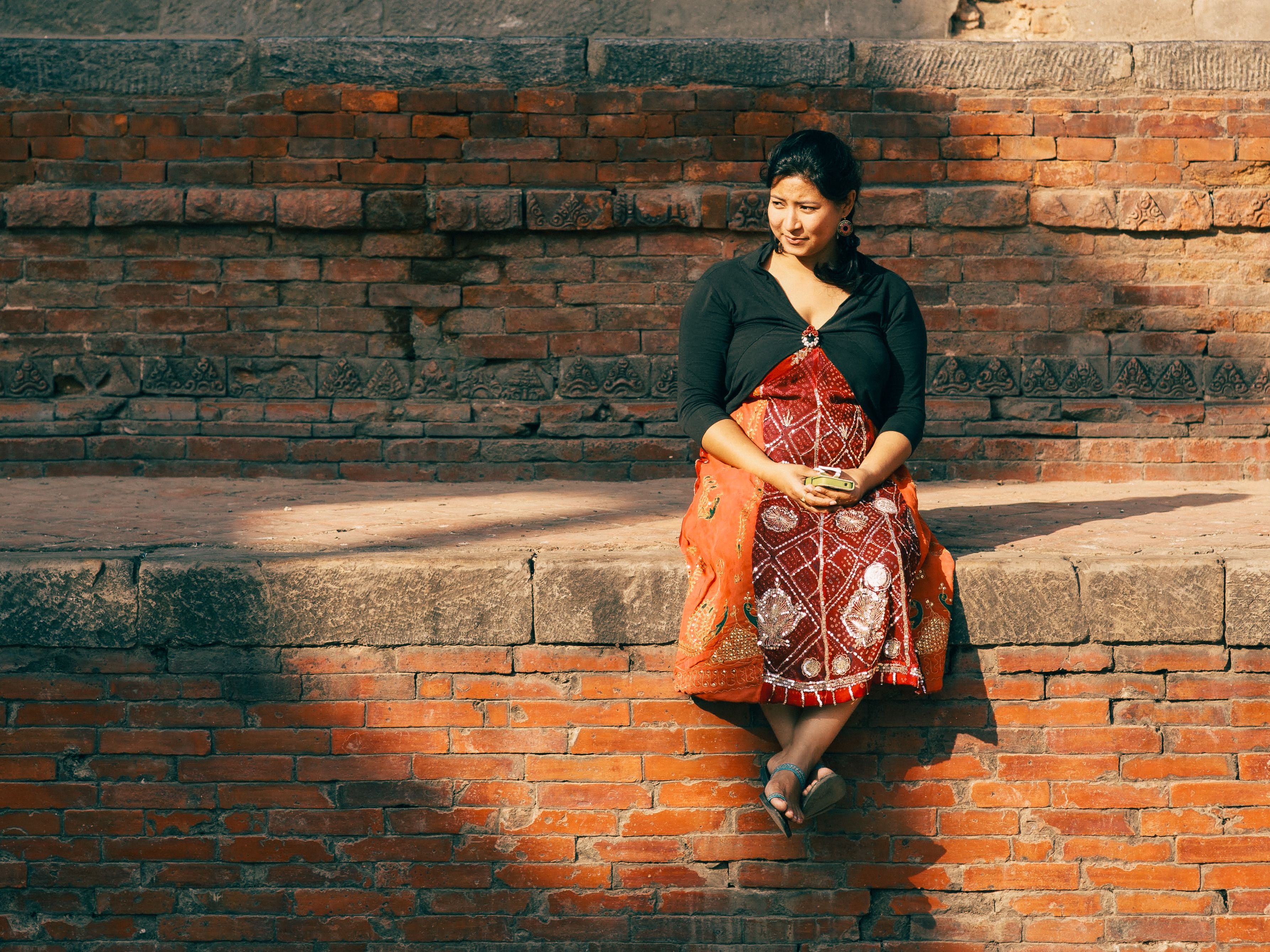 Woman in Black Cardigan Sitting on a Brick Platform · Free Stock Photo