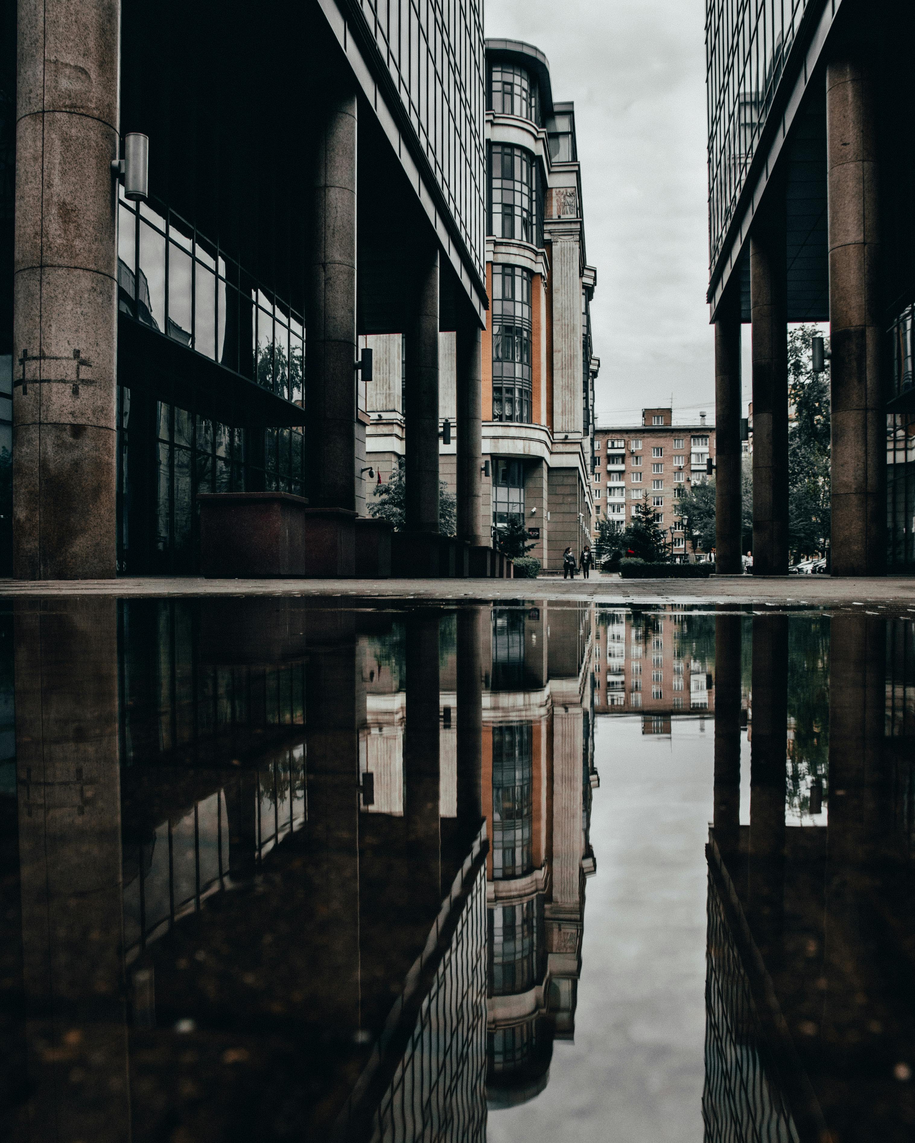 Reflection of Concrete Buildings on Puddle of Water · Free Stock Photo