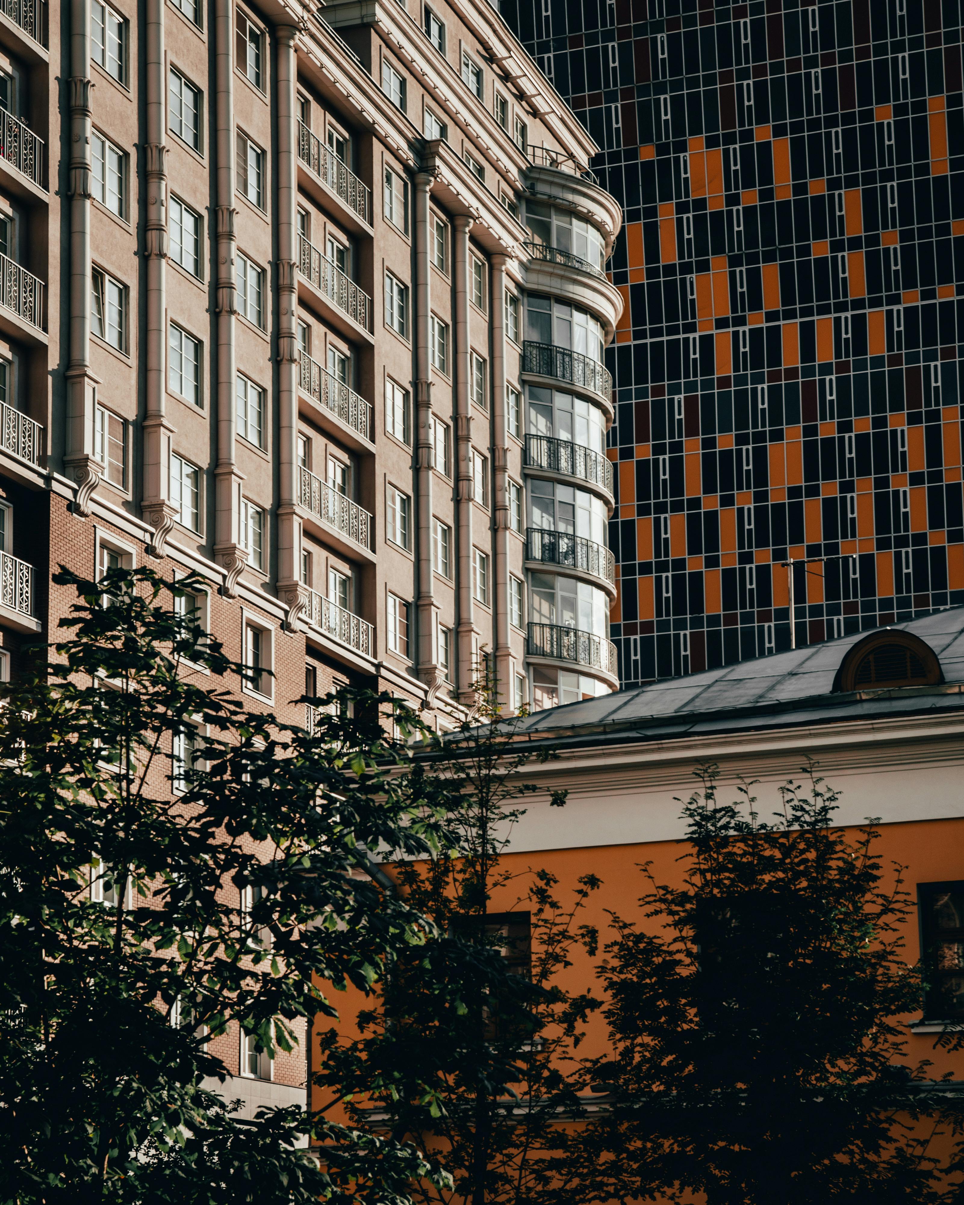 A Beige Concrete Building Beside a Black and Orange Building · Free ...
