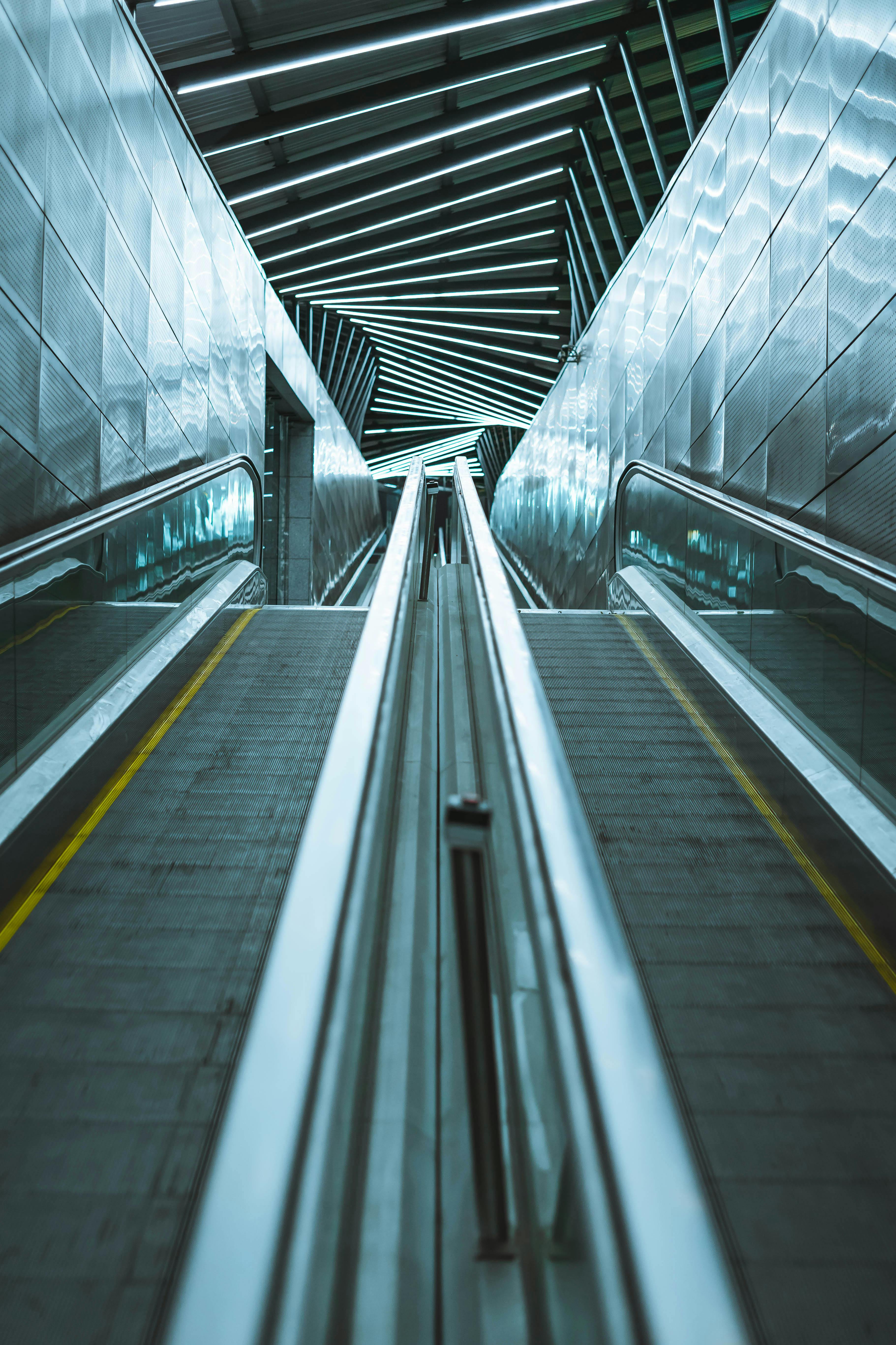 Person Climbing Staircase Between Escalators · Free Stock Photo