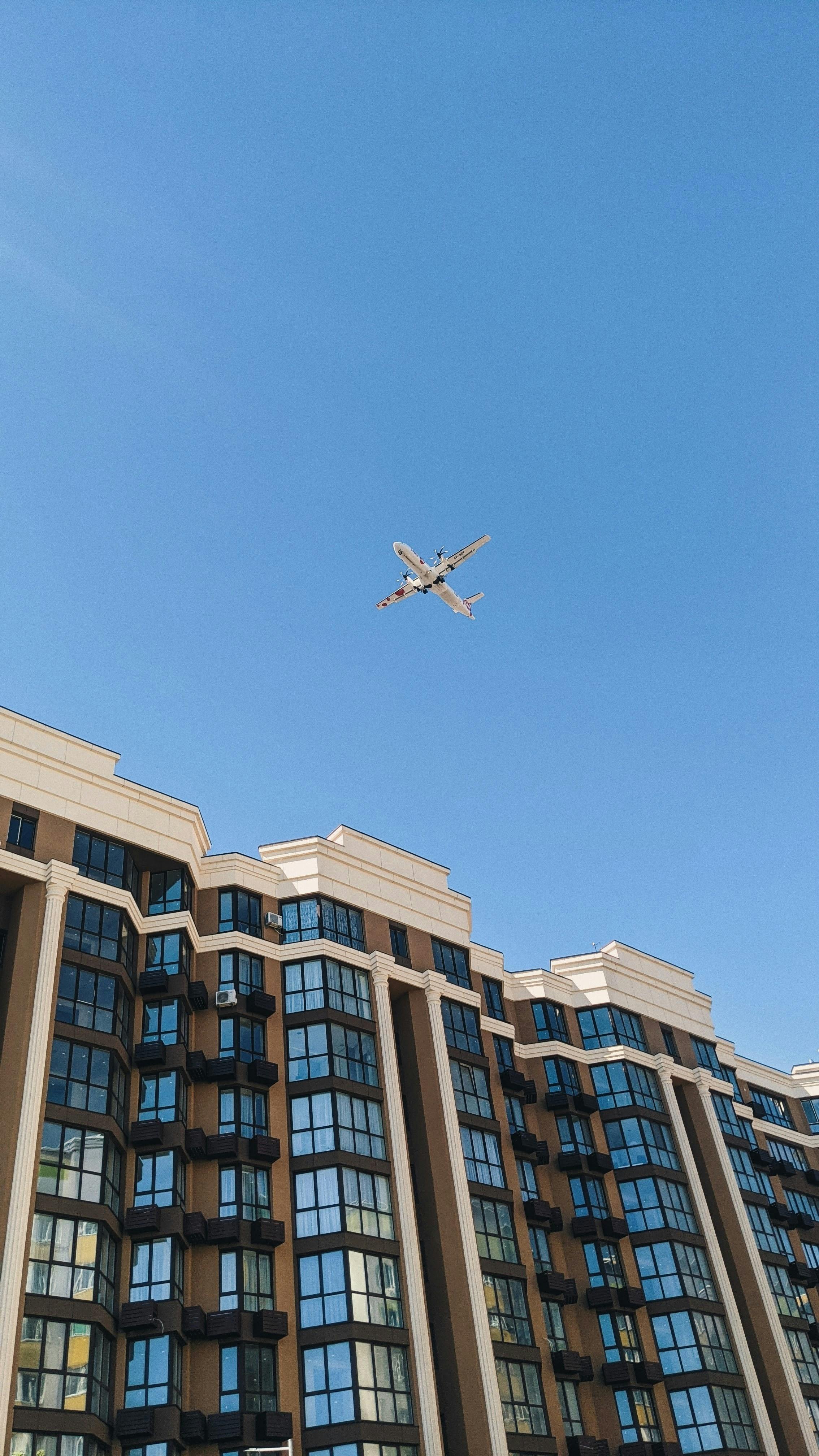 Airplane Flying over Building · Free Stock Photo