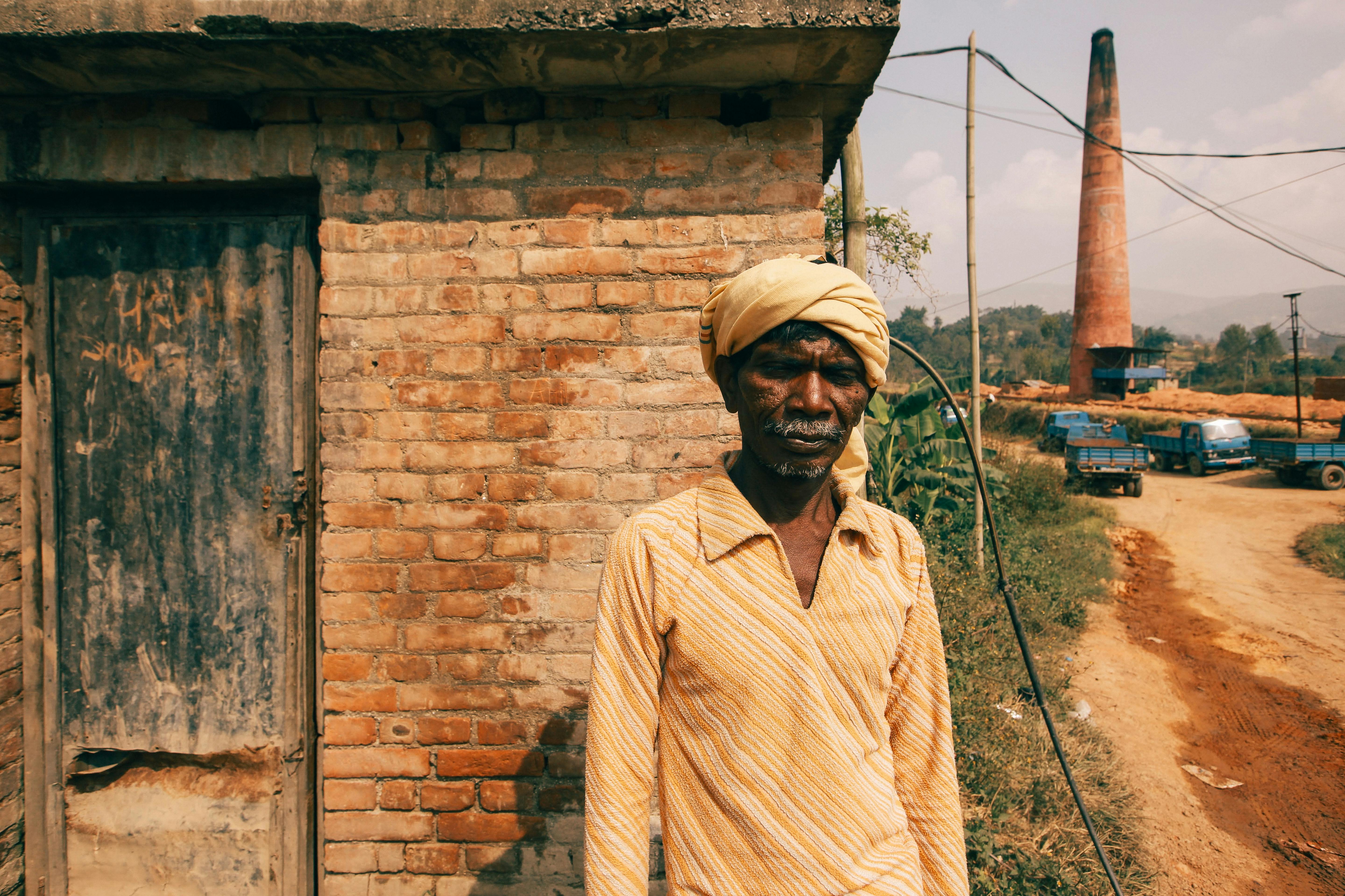 A Man in Yellow Long Sleeves Wearing Sadhu while Standing Near Brick ...