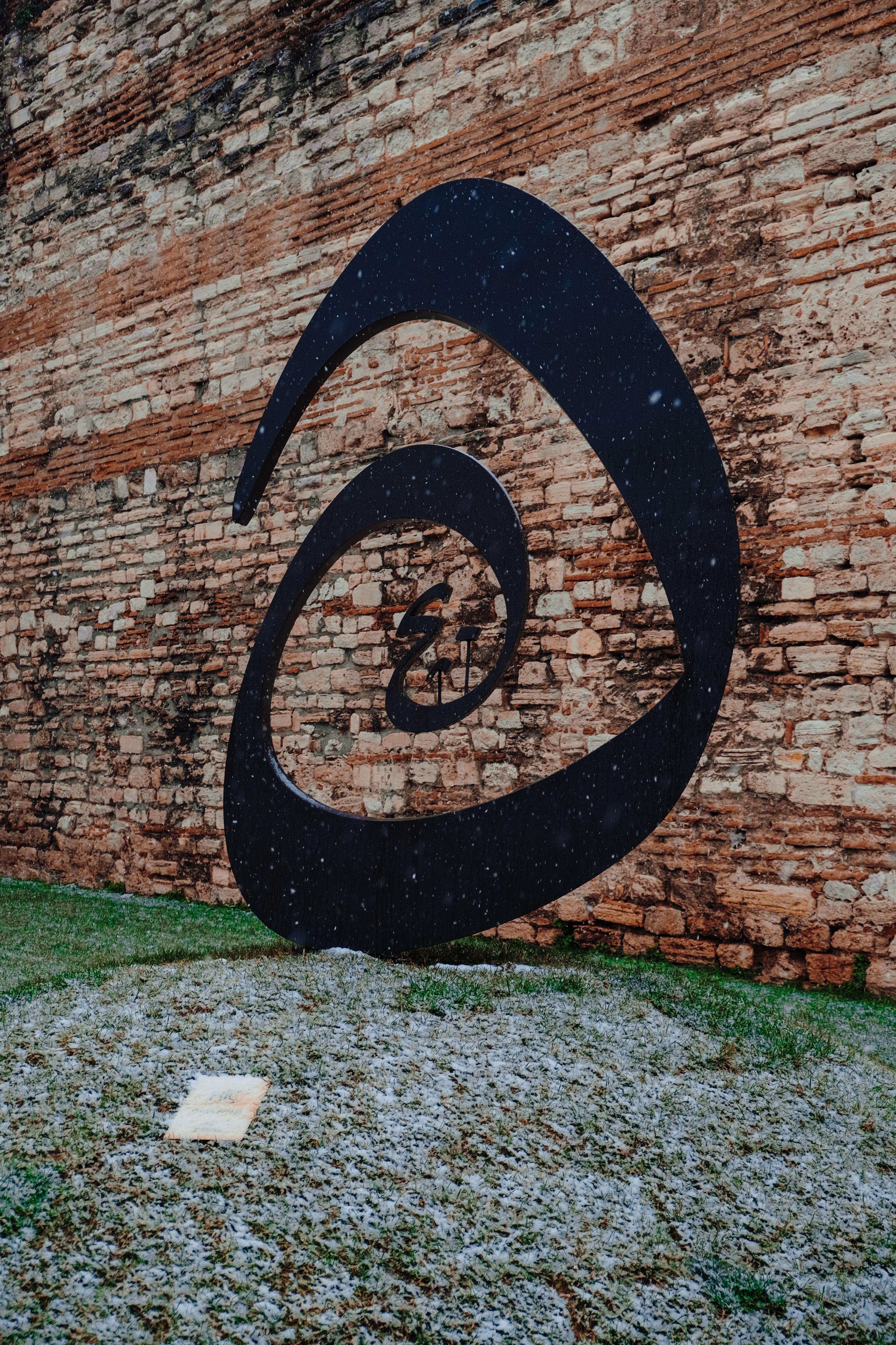 Spiral Sculpture in front of Brick Wall · Free Stock Photo