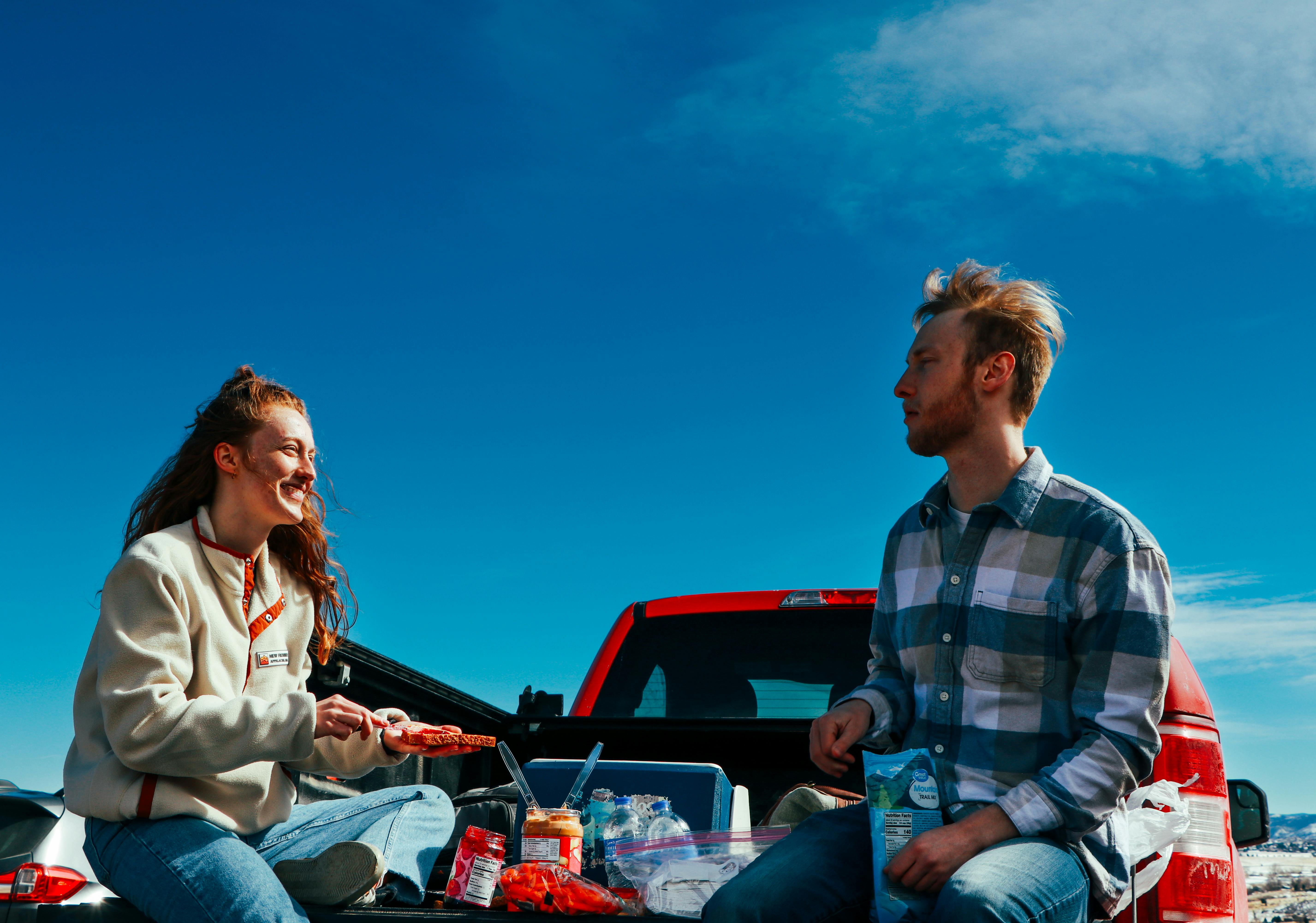 Man and Woman Sitting on the Back of a Pick Up Truck · Free Stock Photo