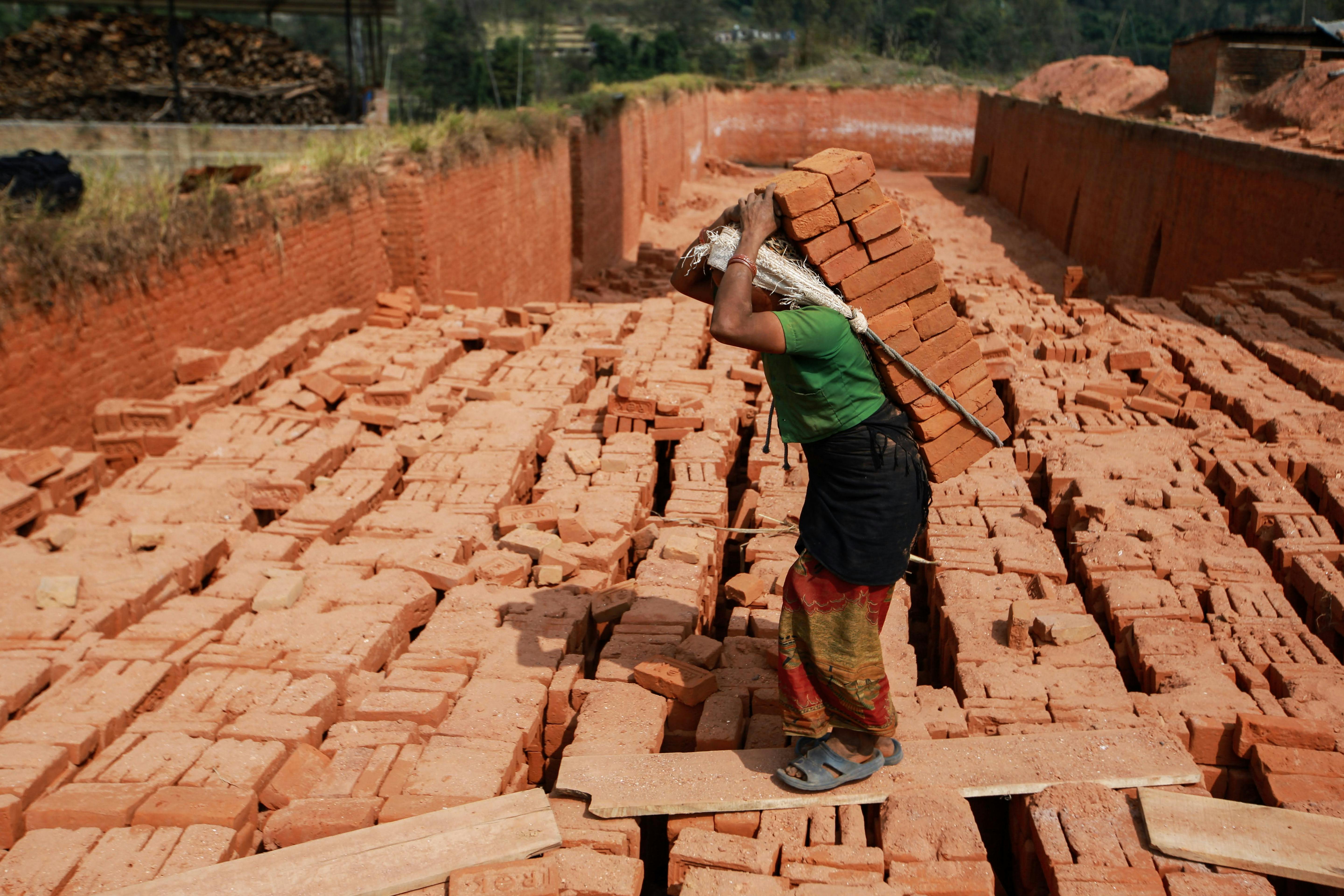 A Person Carrying Bricks on her Back while Working · Free Stock Photo