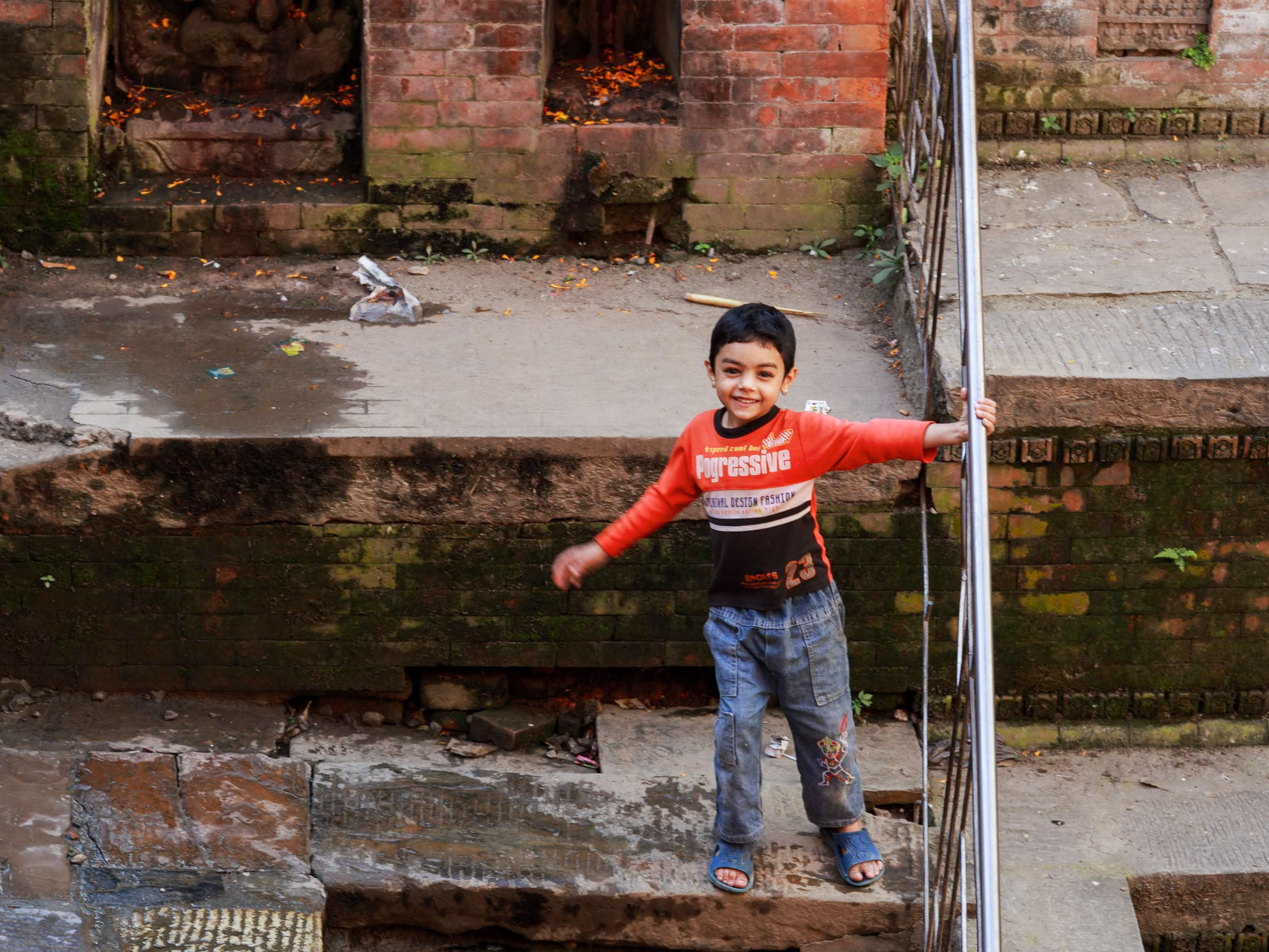 Smiling Boy Standing behind Wall · Free Stock Photo