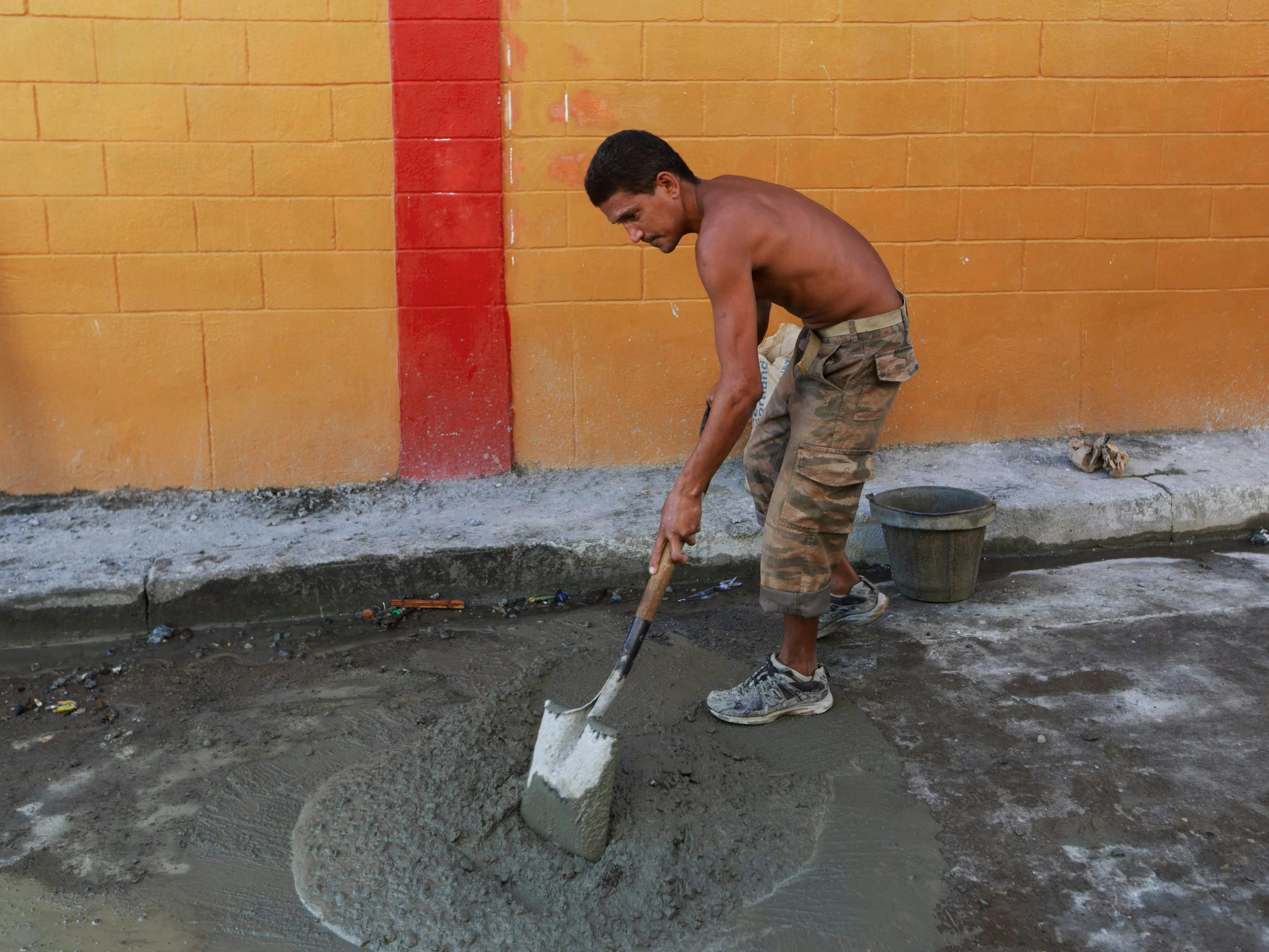 A Shirtless Man Mixing Cement with a Shovel · Free Stock Photo