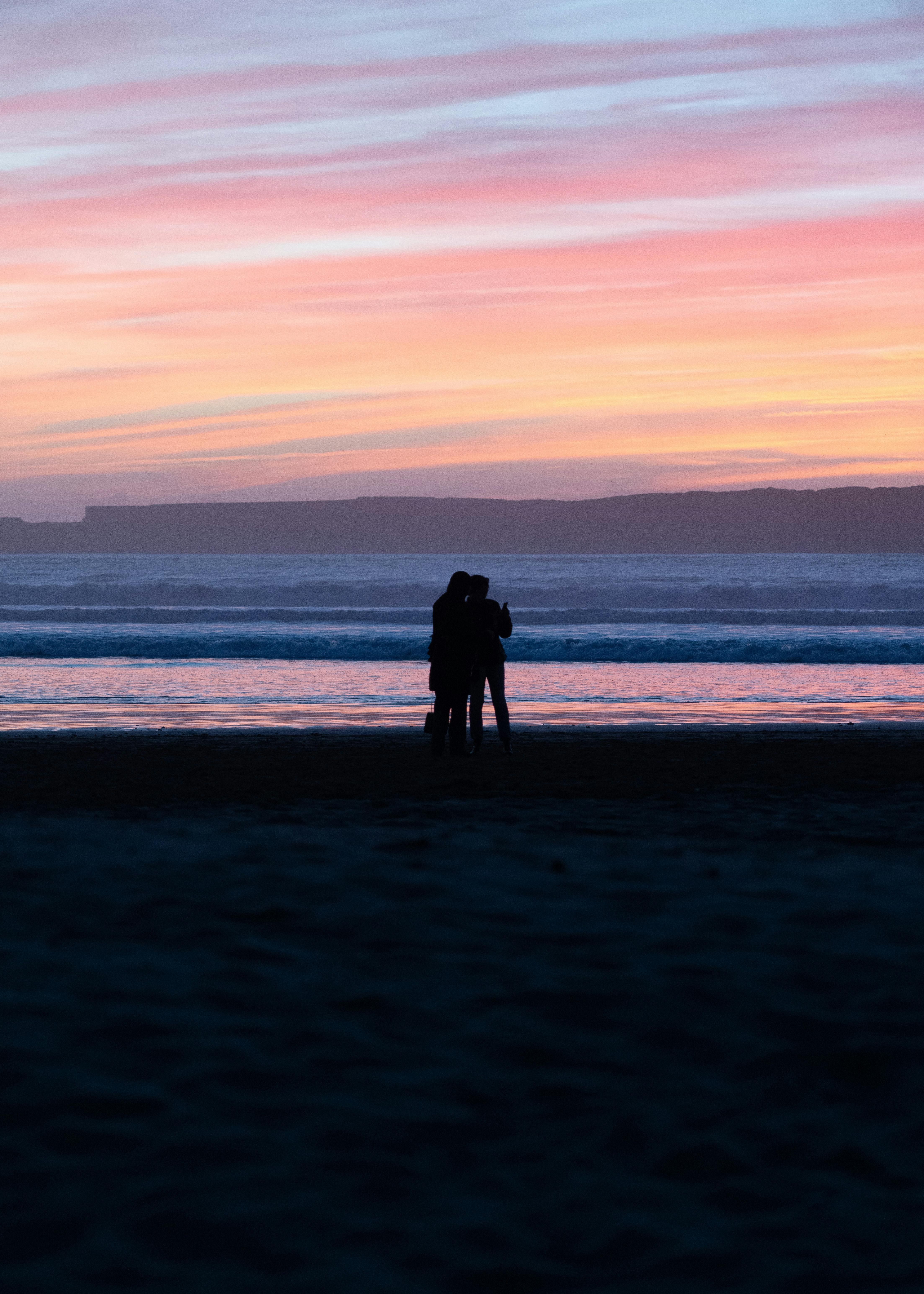 Silhouette of Two People on a Beach During Sunset · Free Stock Photo